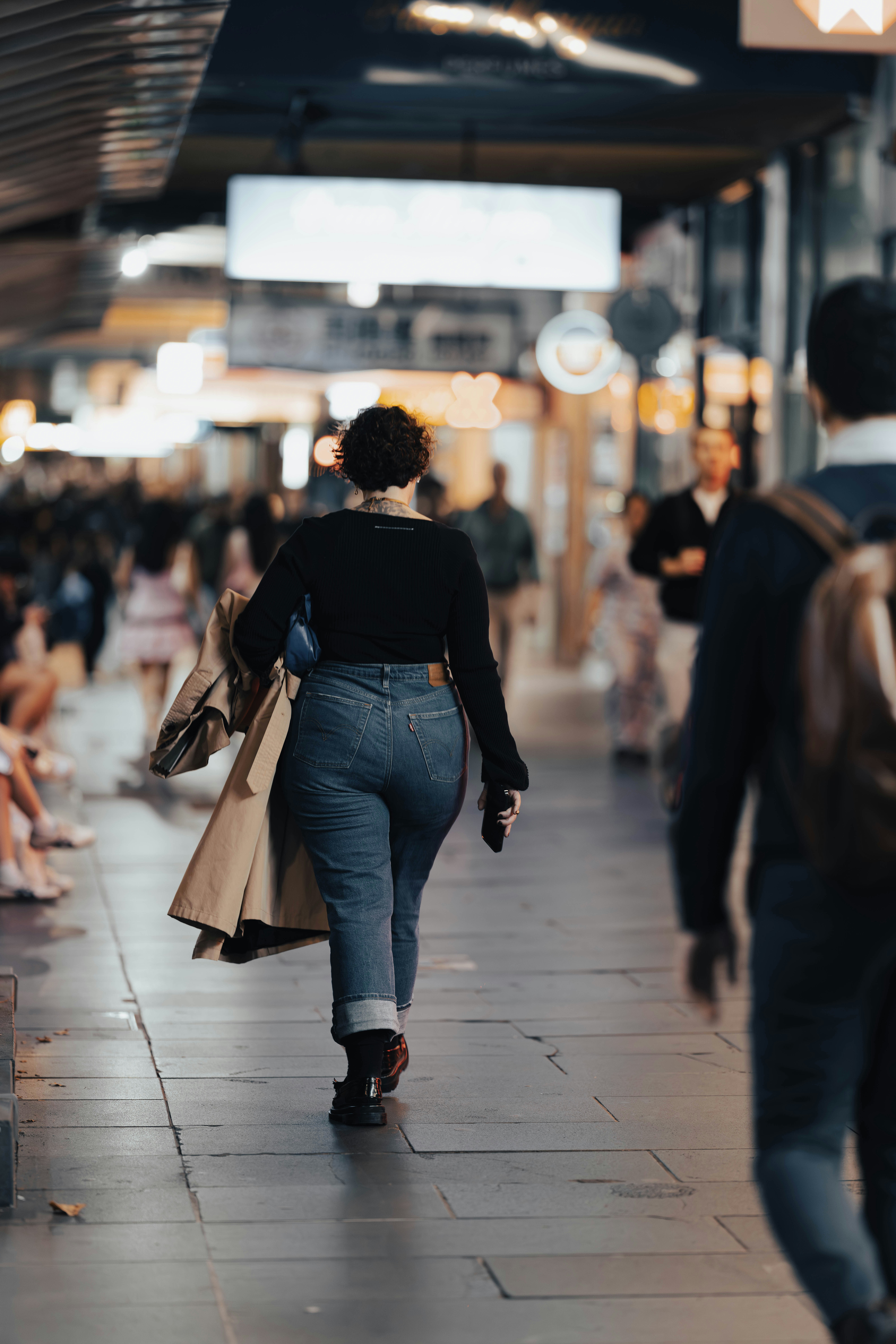 Solemn Stride: A Woman Walking Through a Bustling Corridor