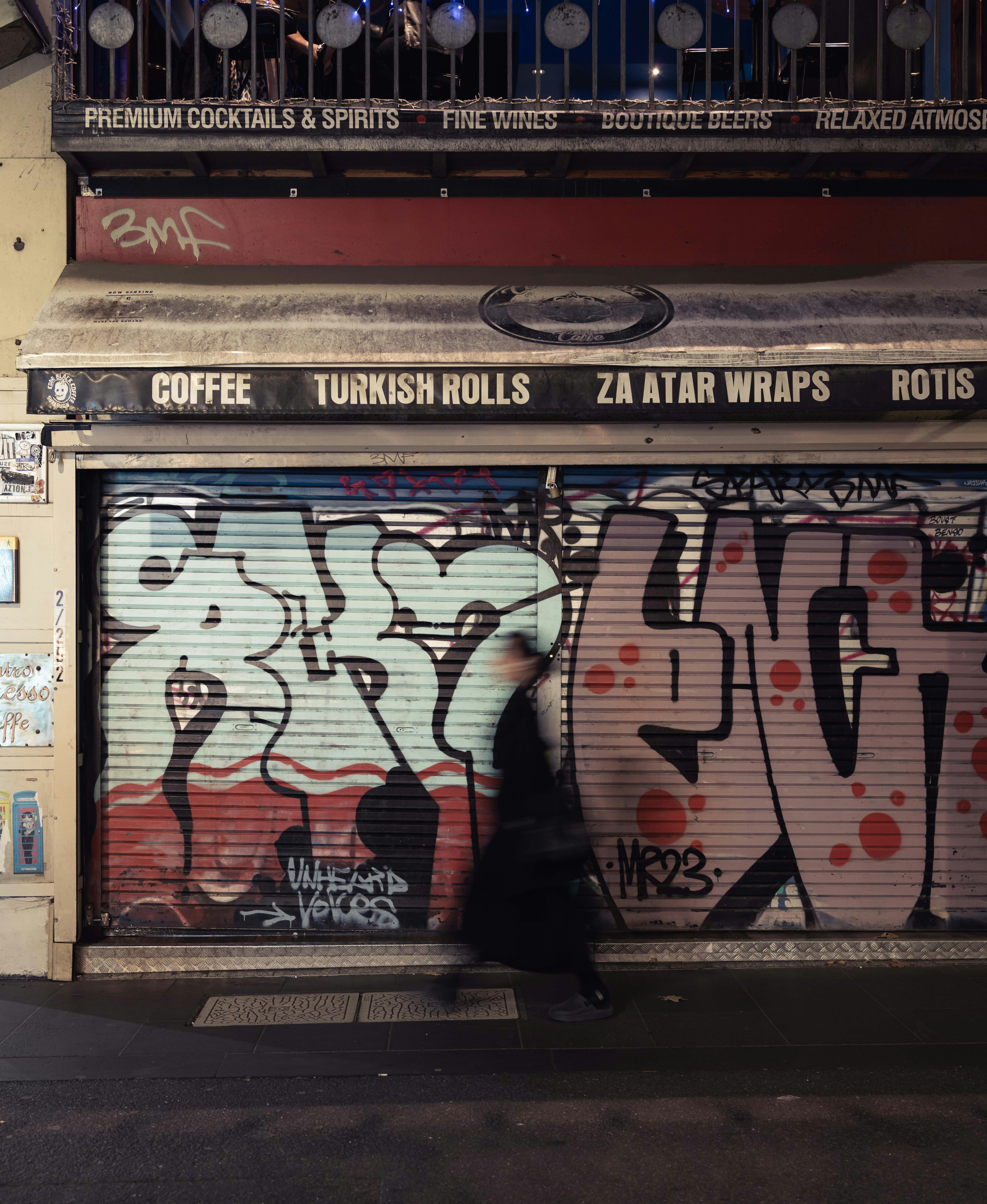 Midnight Roll-Down: Graffiti Framed by a Shadowy Pedestrian