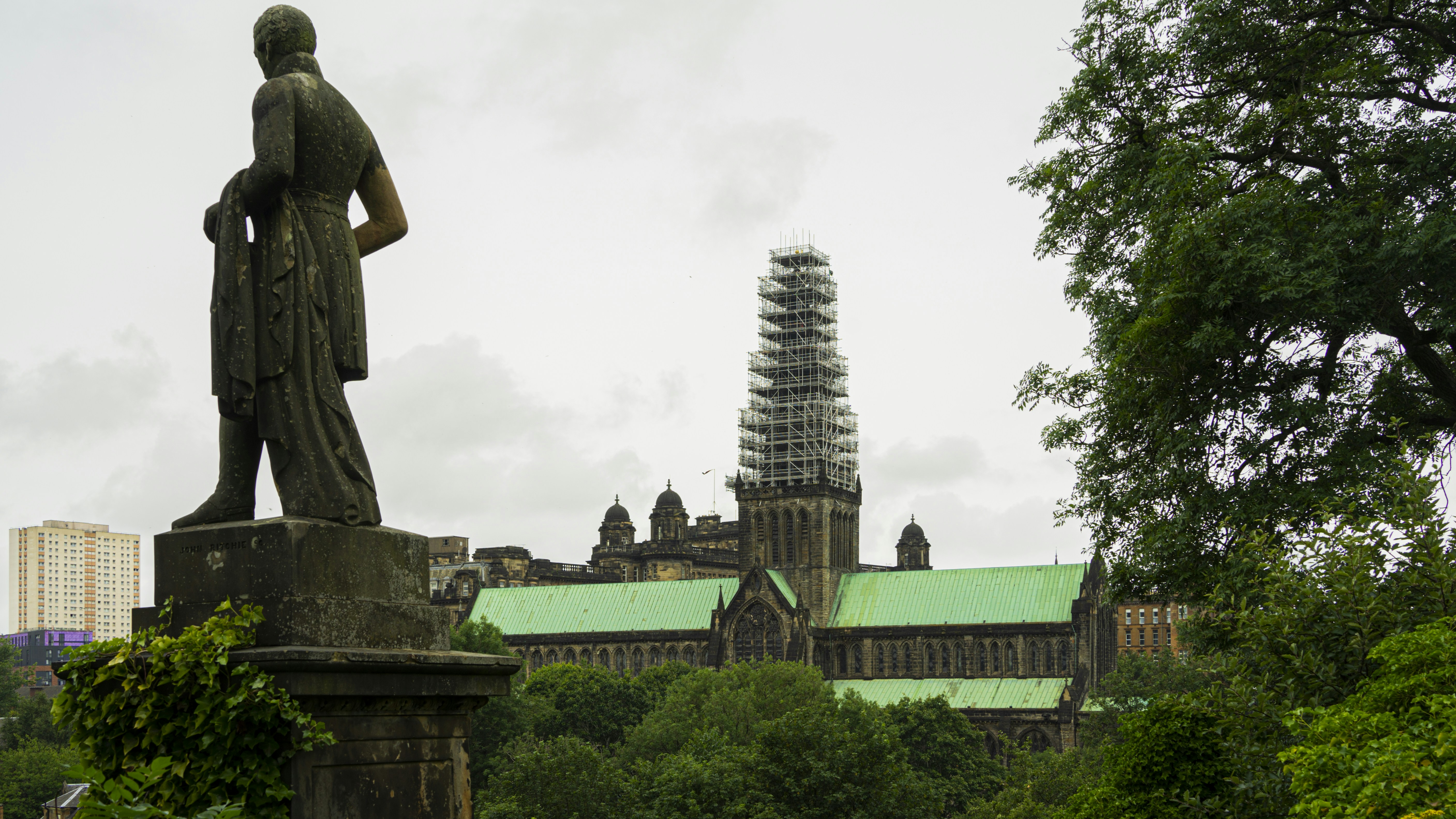 Statue Overlook: A Historic Cathedral Rising Beyond Green Canopy