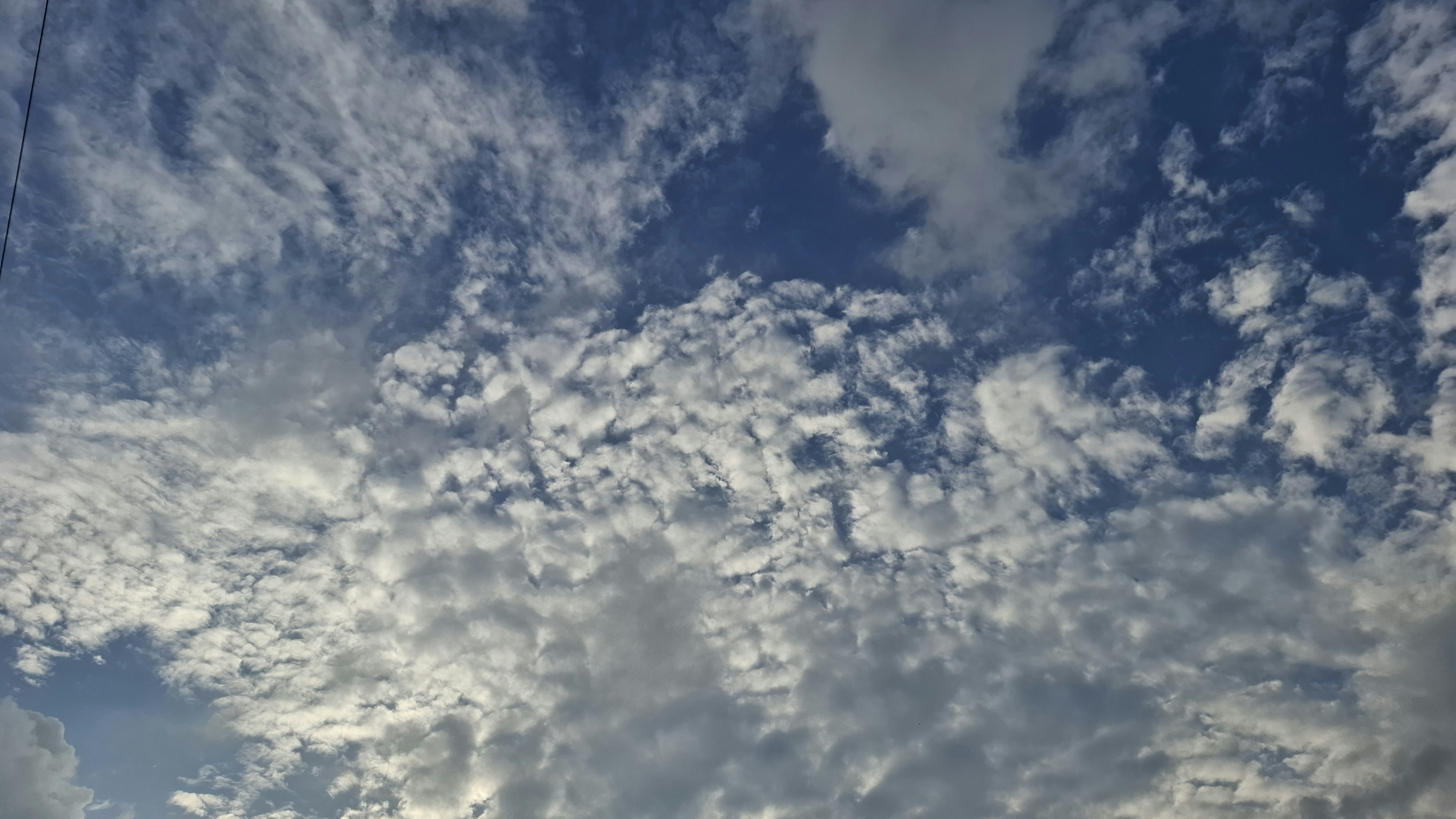 Expansive sky filled with textured clouds over a calm horizon, emphasizing natural light and depth.