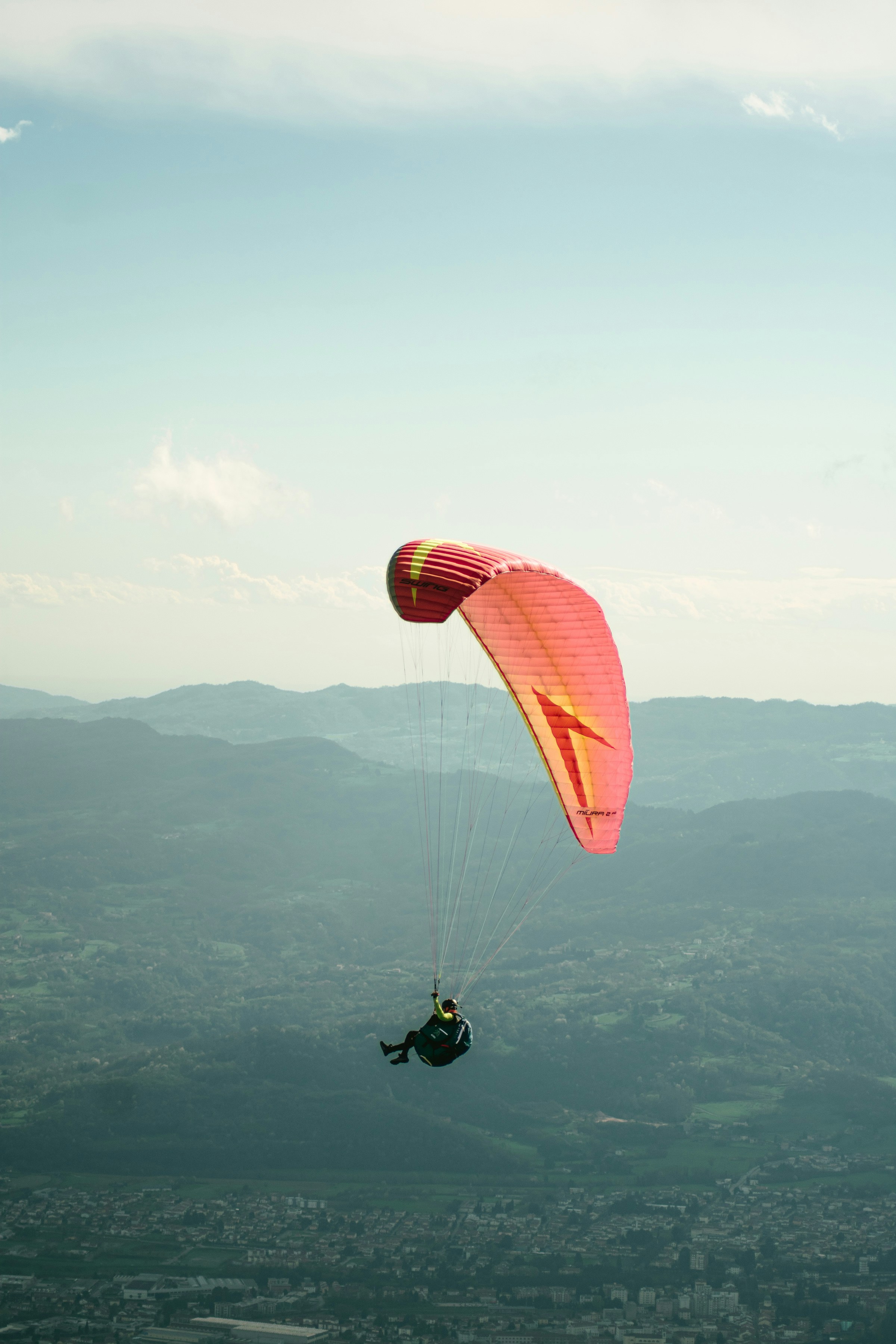 Red Parachute Soaring Above Valleys