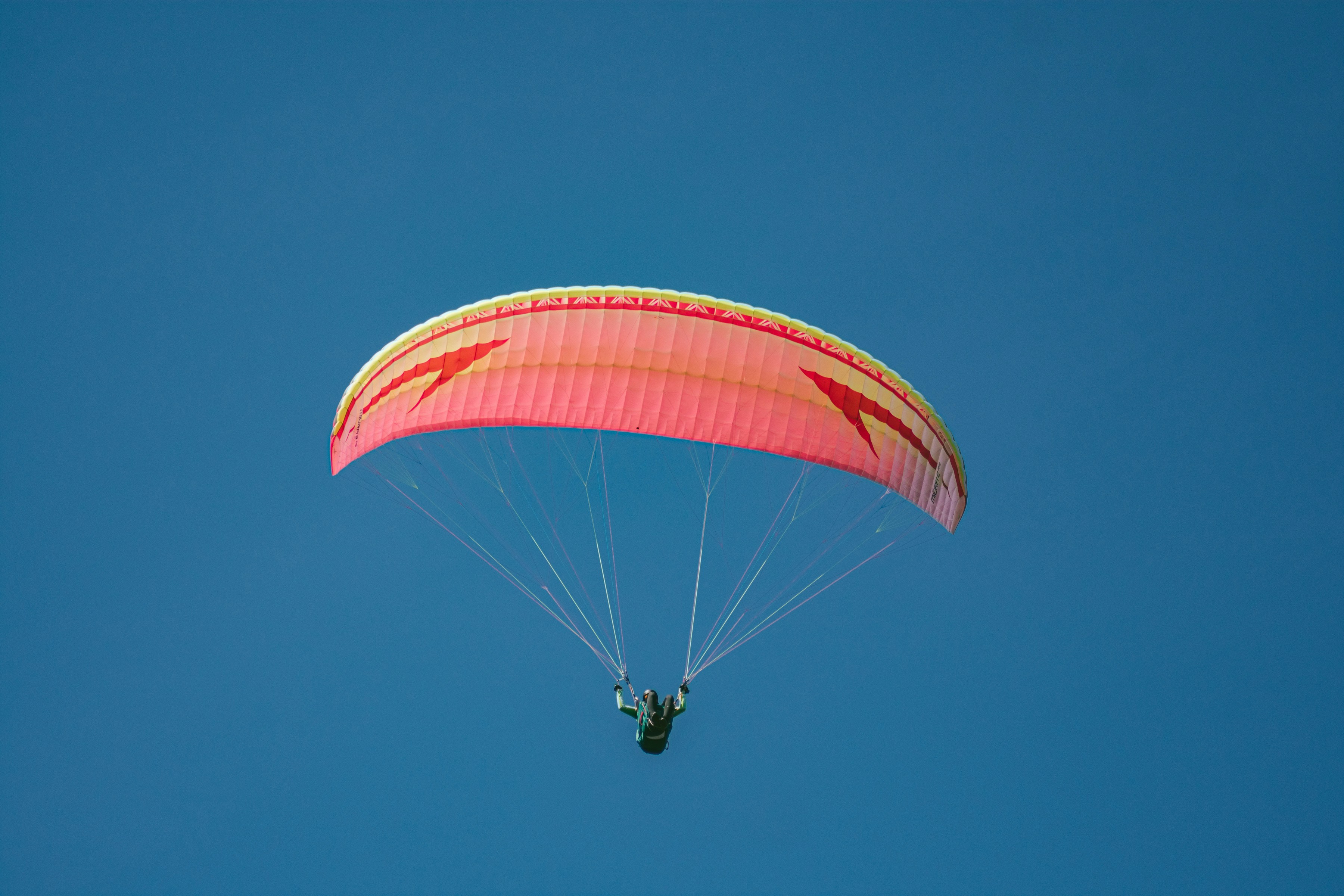 Crimson Wing: A Solo Paraglider Against a Cerulean Sky