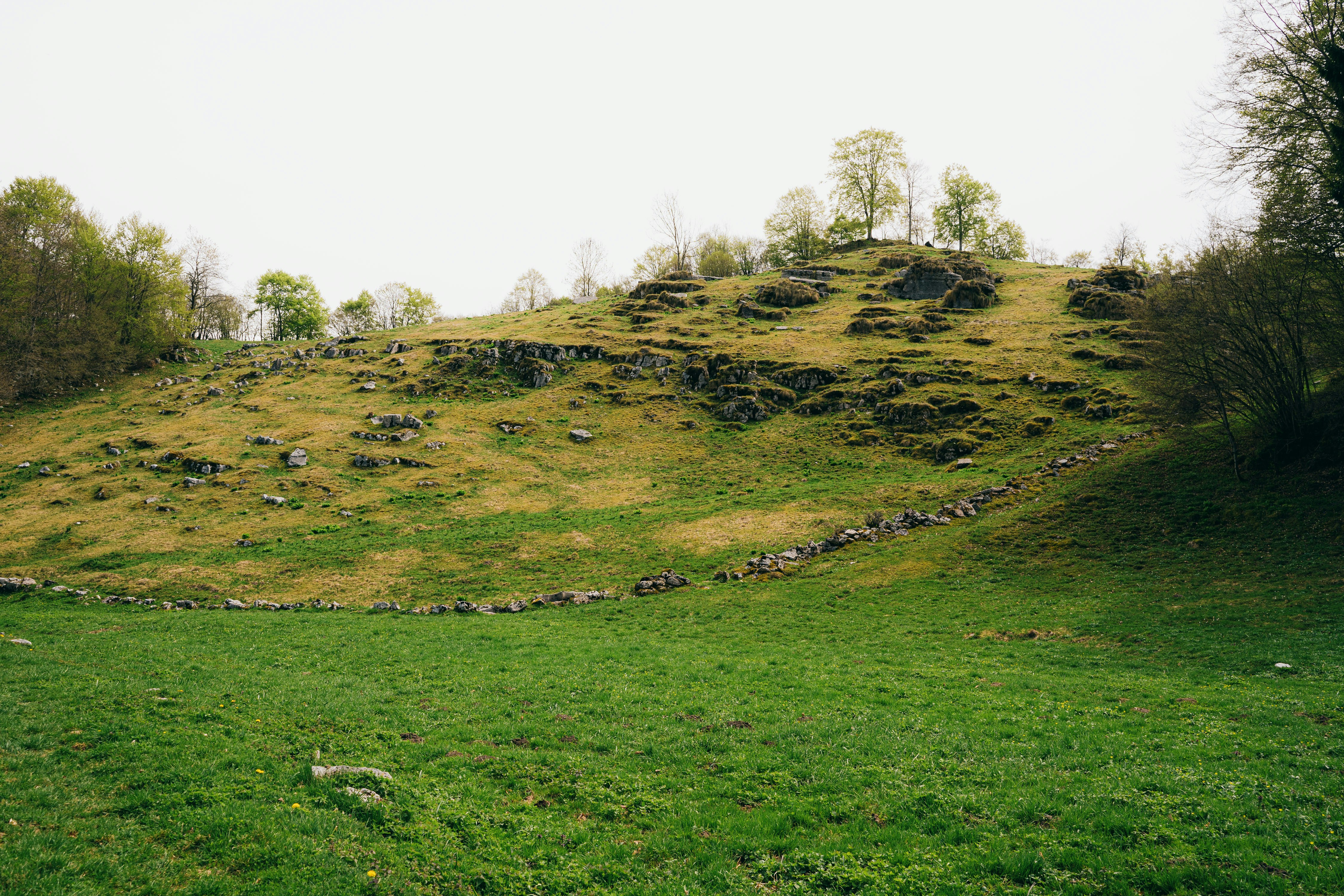 Stone terraces ascend a grassy hillside under a pale sky
