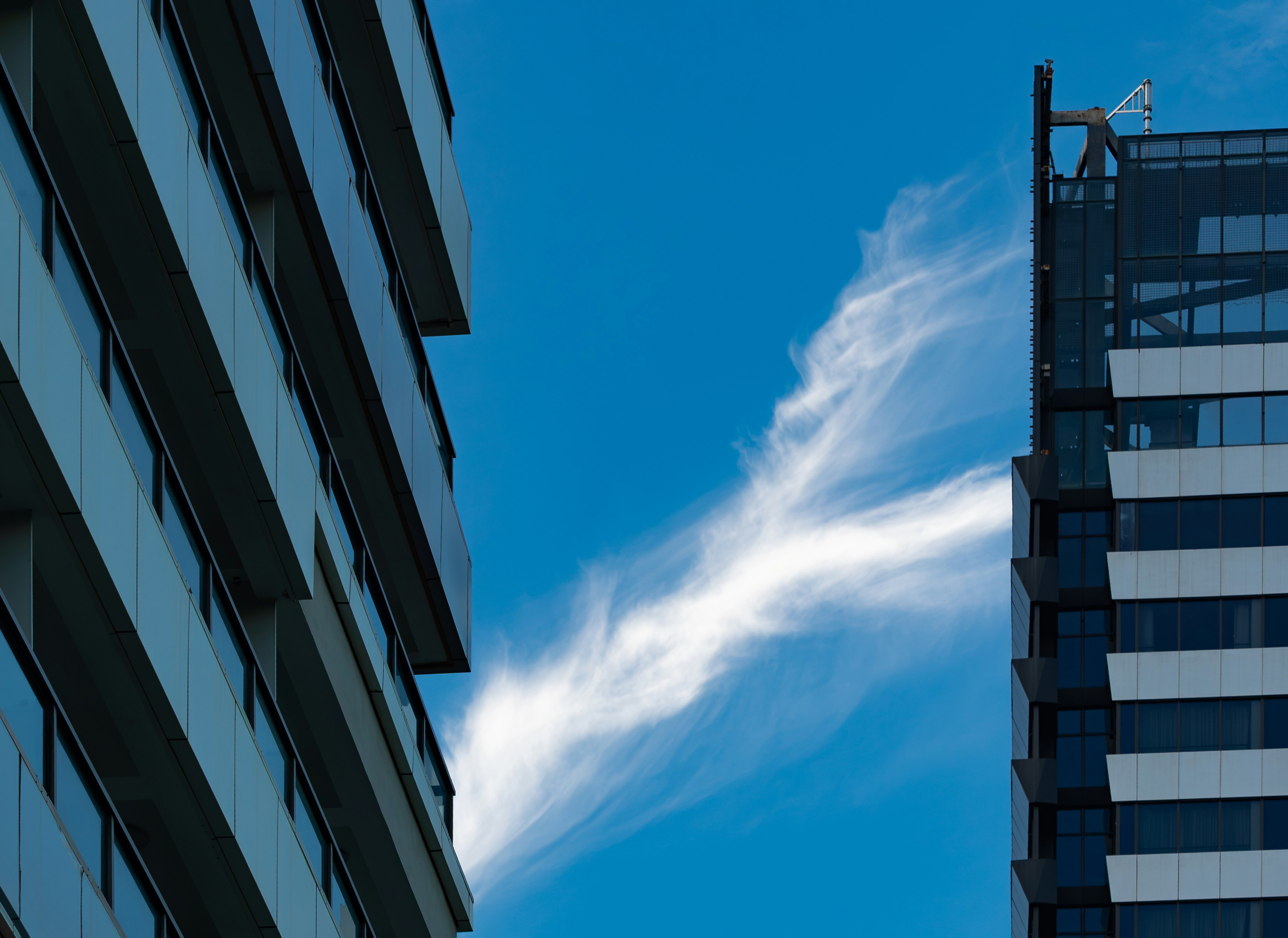 Skyward Gap: Bleached Cloud Weave Between Skyscrapers