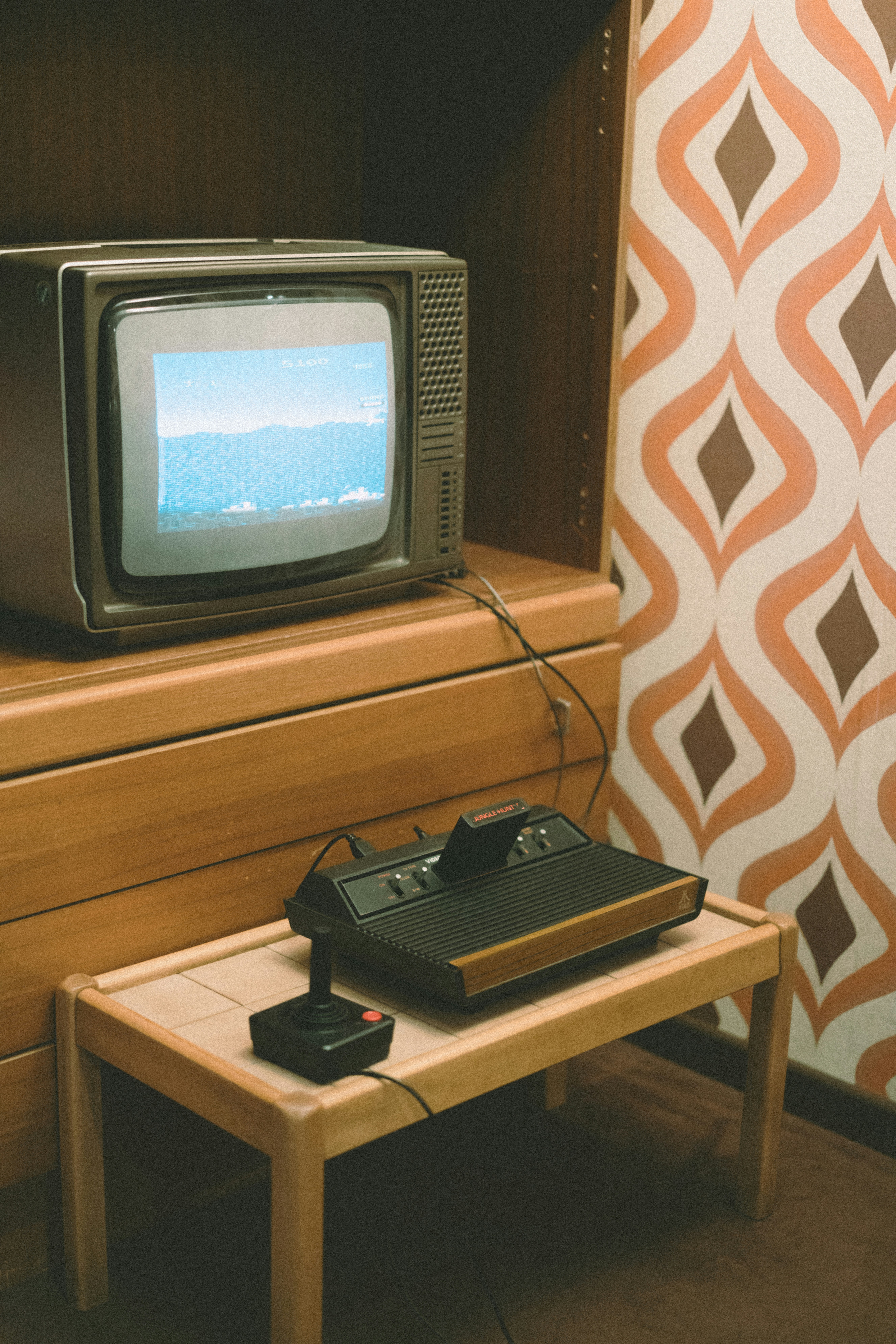 Retro Corner: Vintage TV and Gaming Console Under Warm Edges of an Orange Patterned Wall