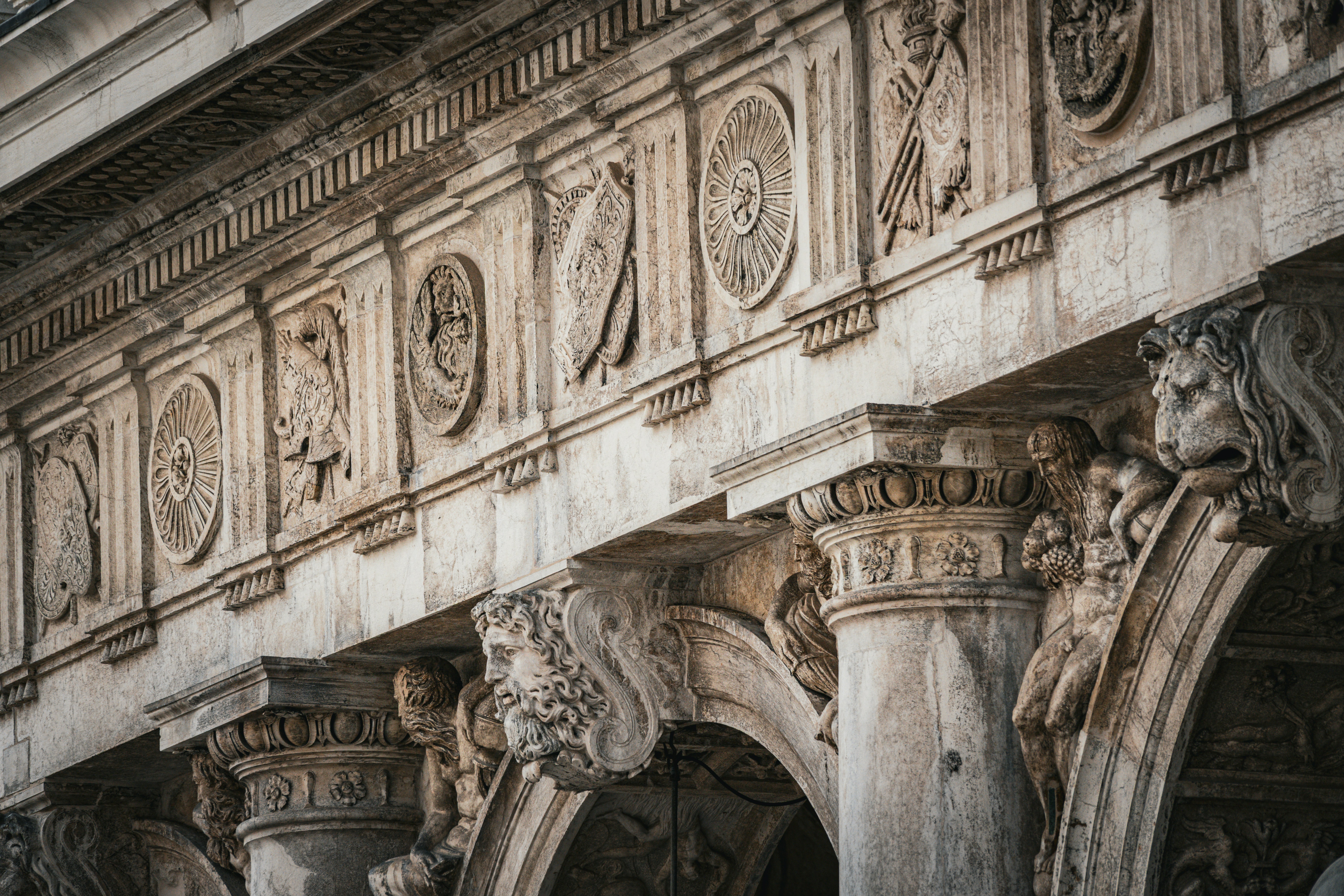 Carved Stone Relics: Faces and Columns Under Arching Light