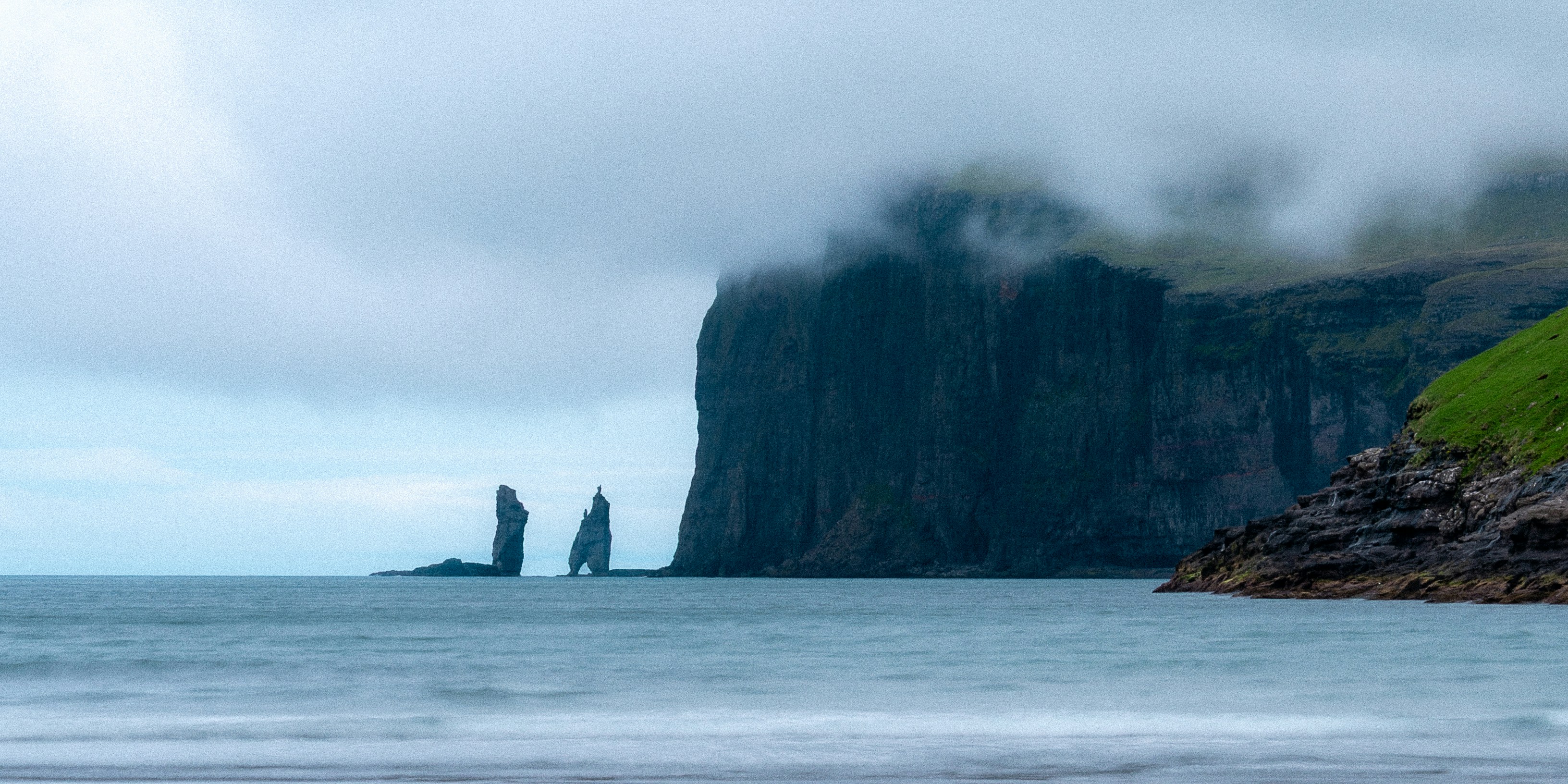 Sea Stack Silhouettes Beneath a Cloud-Capped Cliff