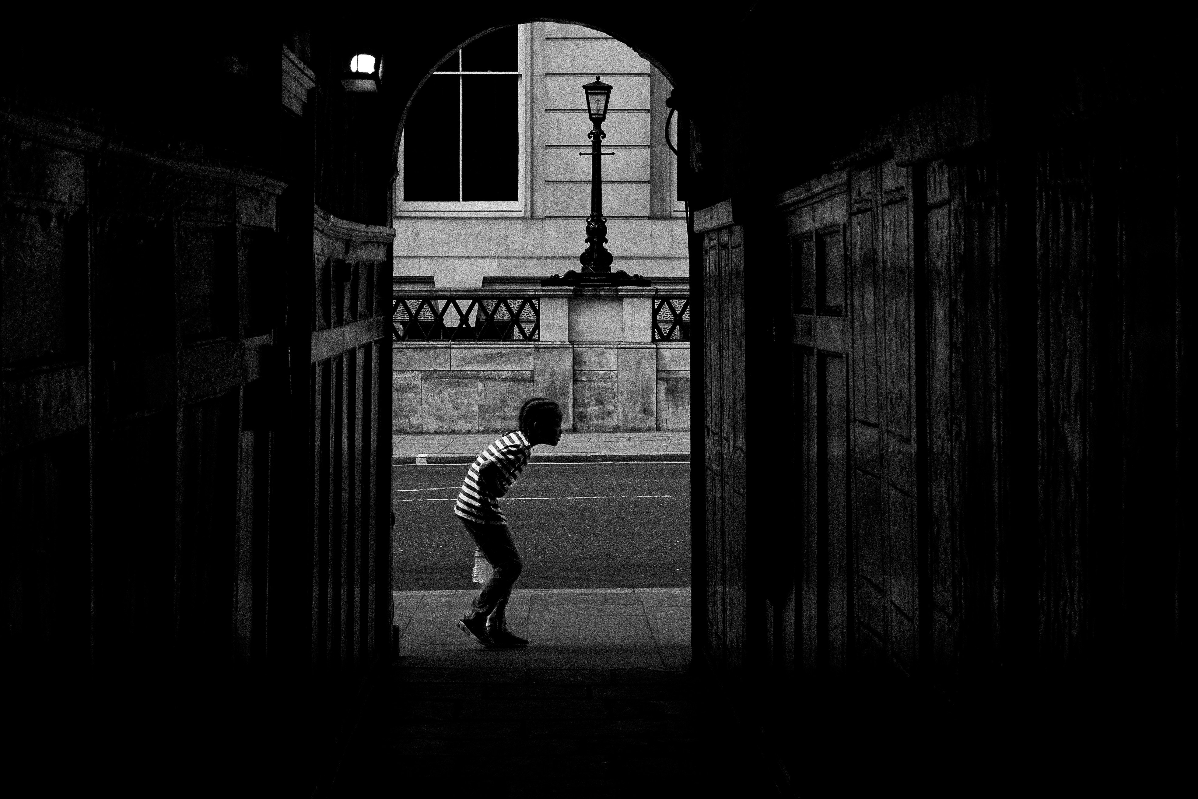 Child in the Arch: A Silhouette Against the Street Light