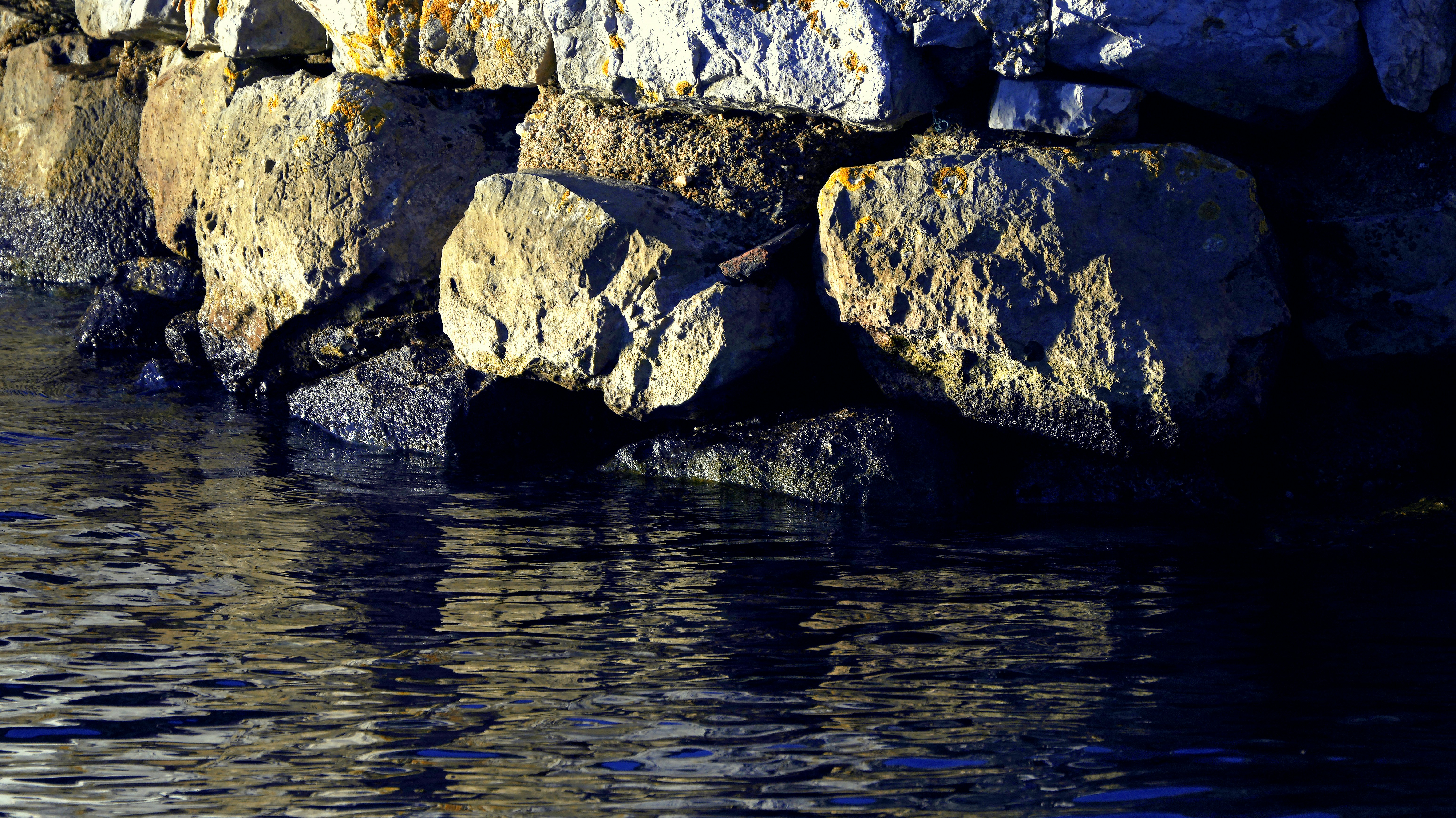 Rugged shoreline: sunlit rocks meeting quiet water