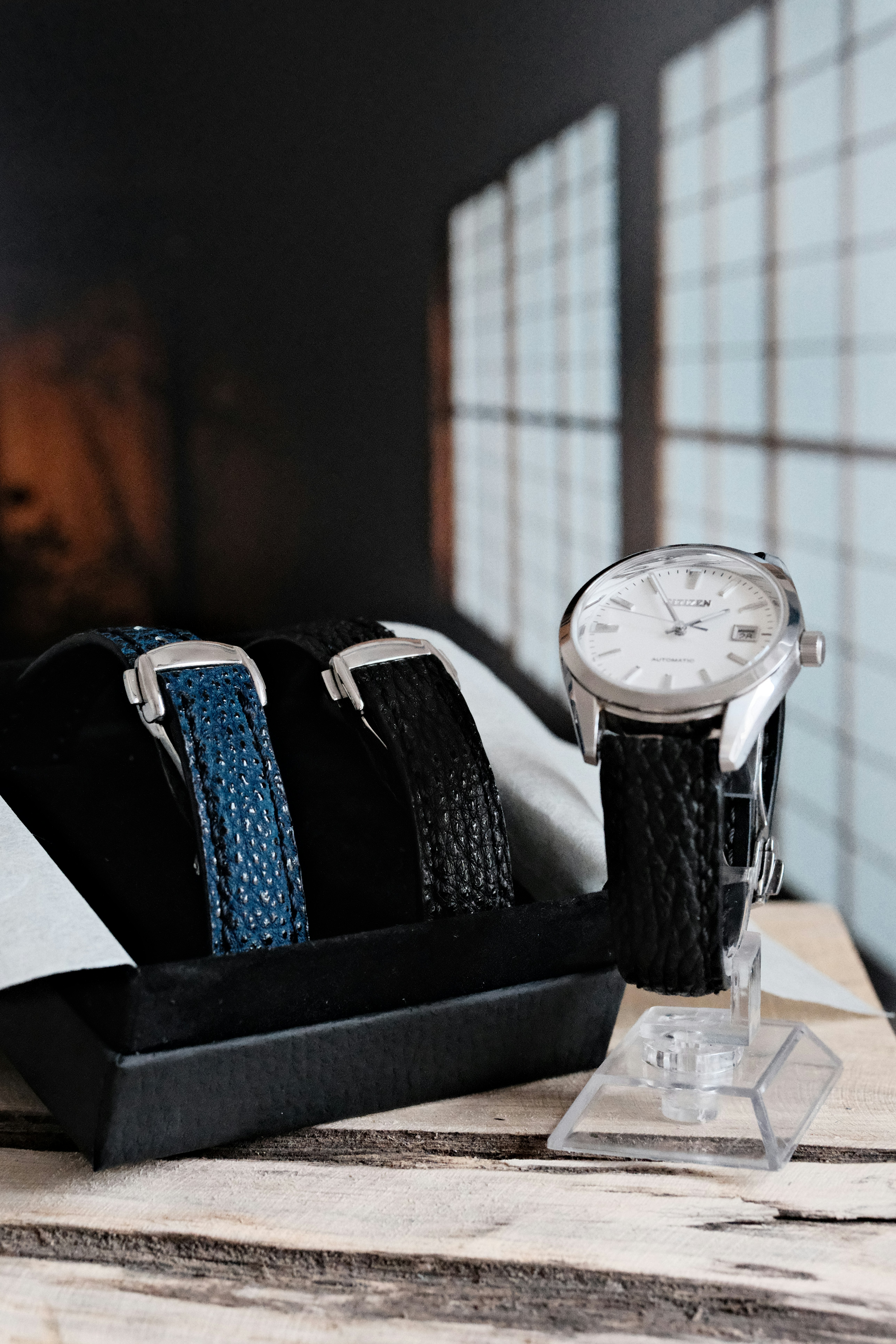 Elegant timepieces on display: a row of leather straps and a silver wristwatch