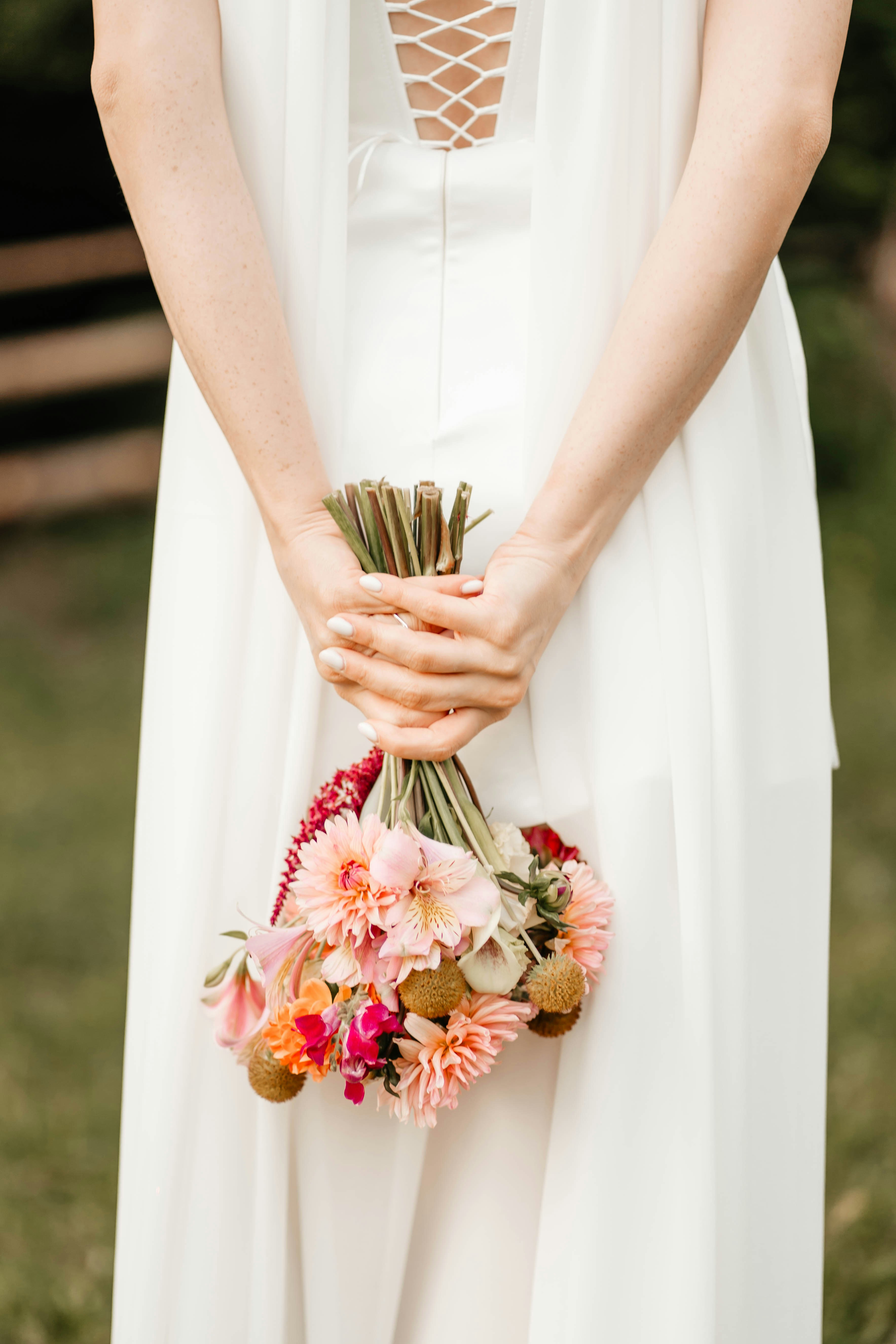 Bride’s bouquet at heart of white dress, softly lit on a sunny day