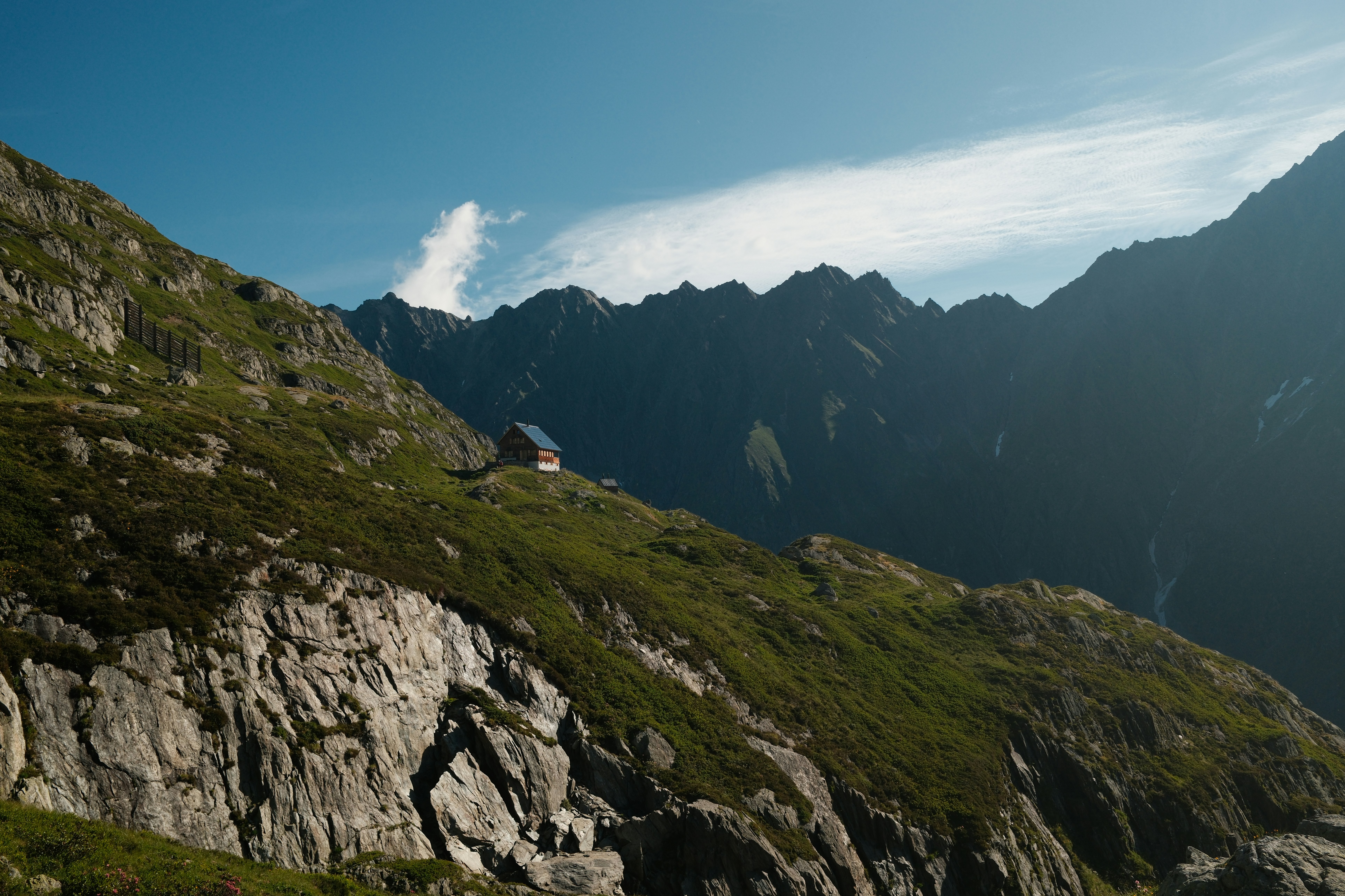 A Quiet Pass Above the Valley: A lone hut perched on rugged slopes