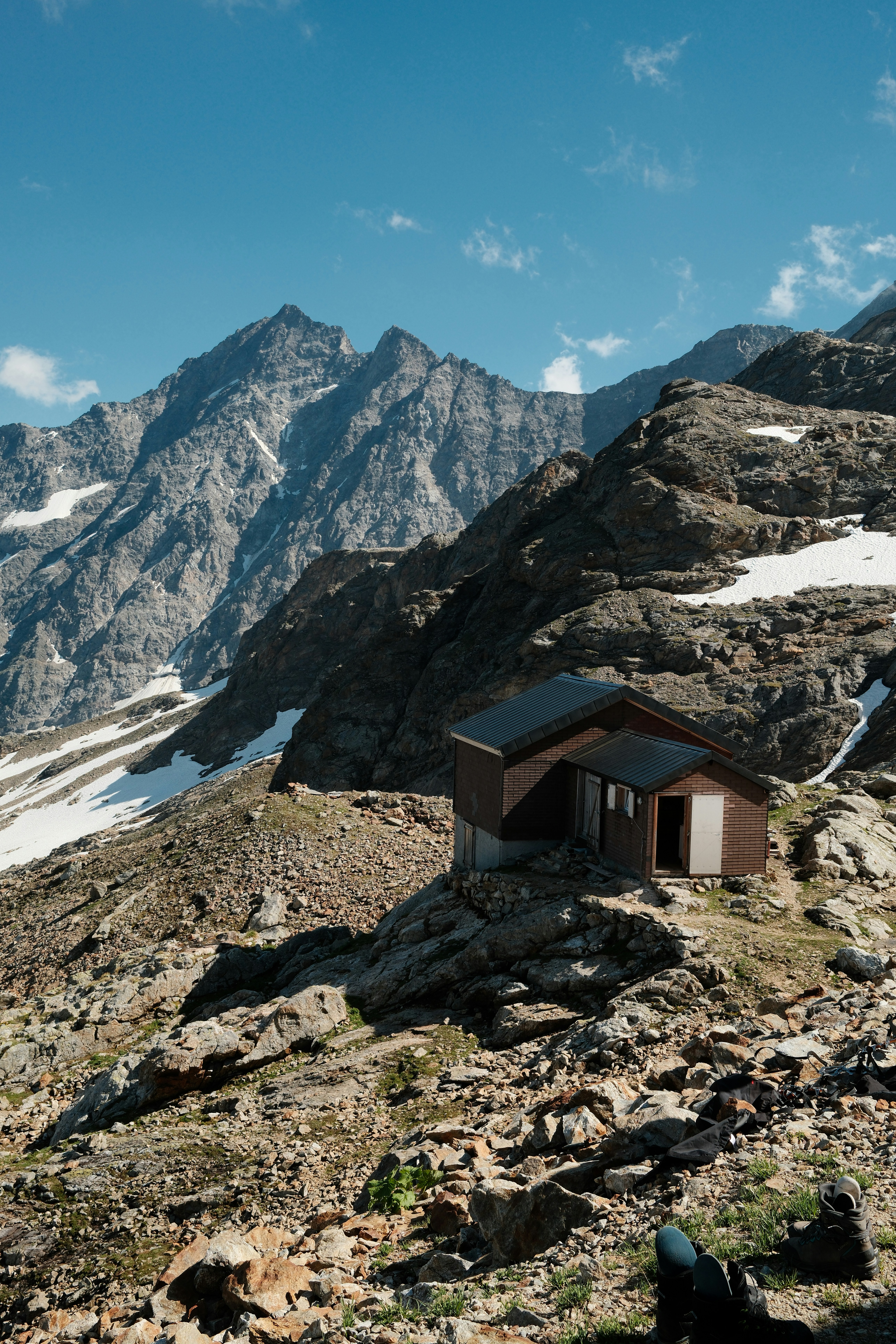 A Highland Refuge: A wooden hut clings to jagged slopes beneath towering peaks