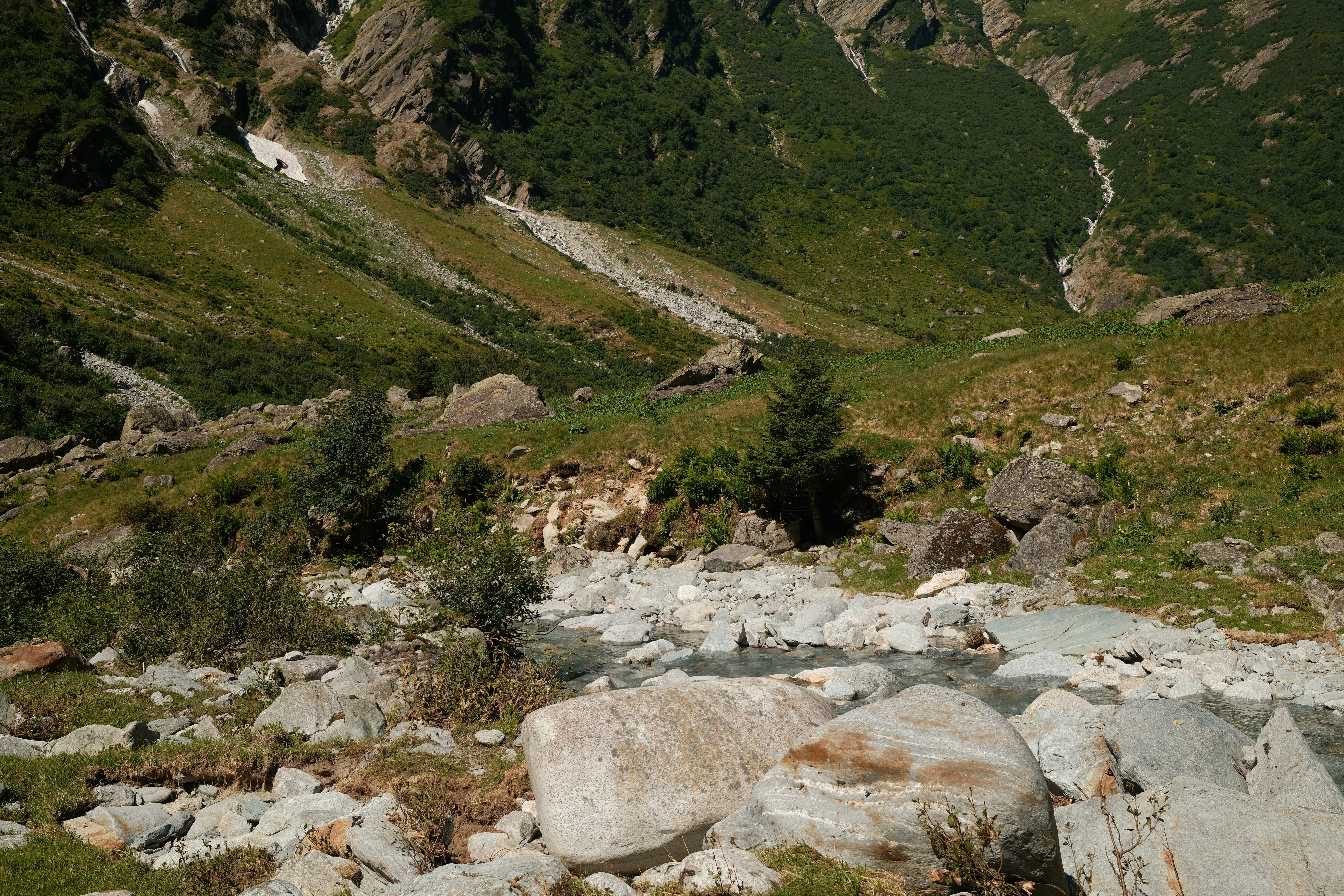 Pebble strewn riverbed framed by alpine slopes
