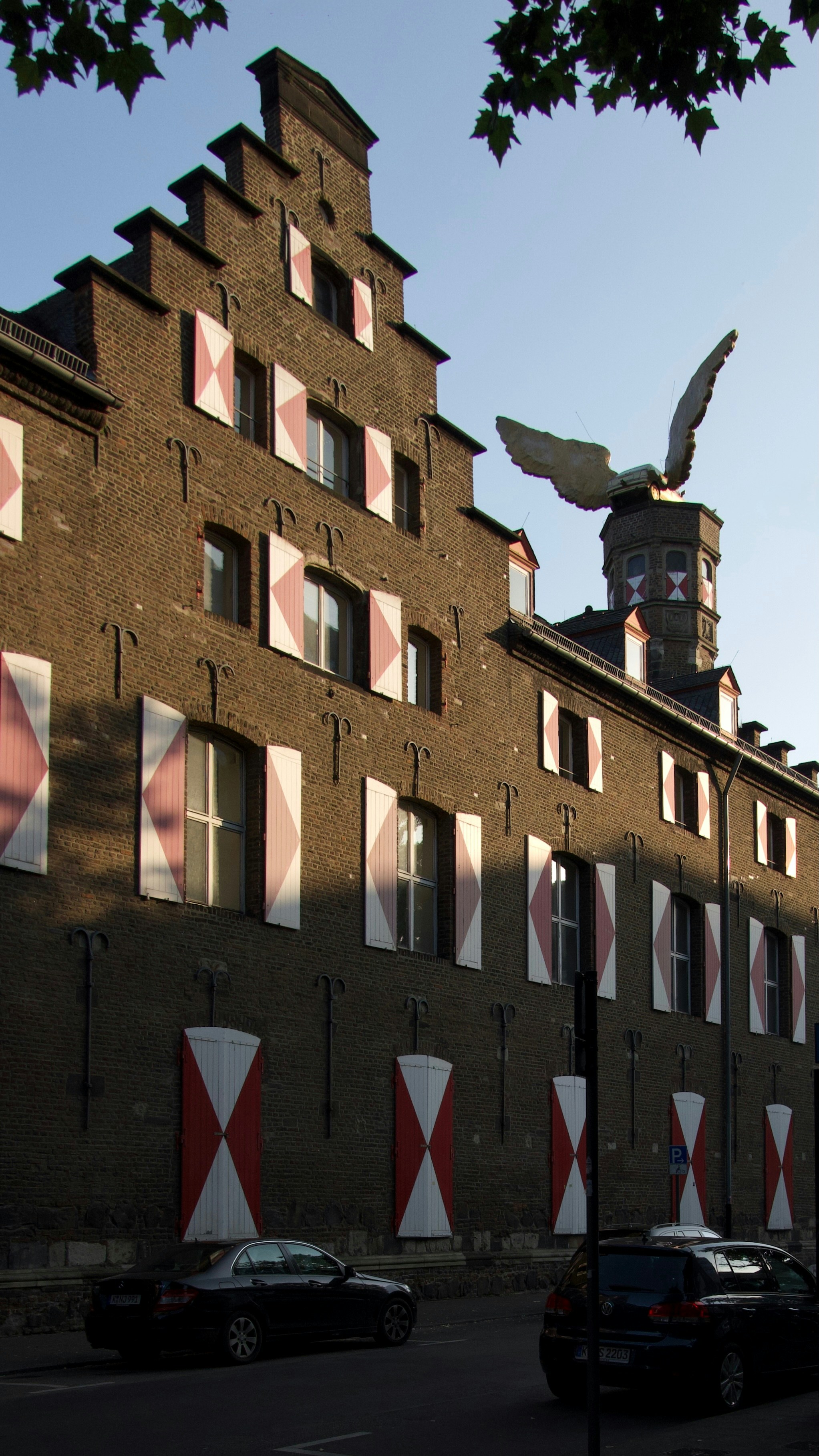 Stepped gable brick building with patterned shutters and eagle sculpture.