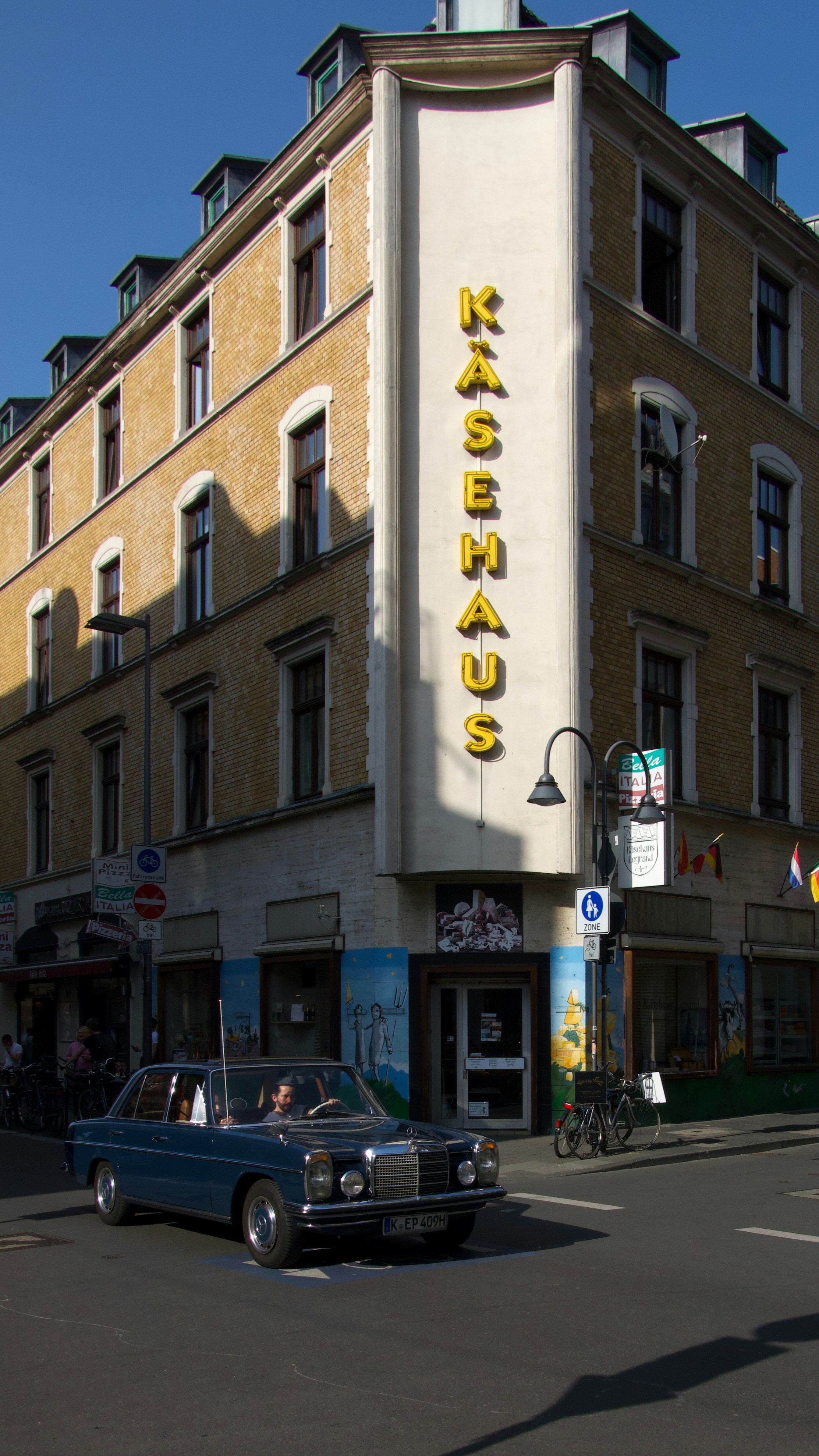 Yellow KASEHAS vertical sign on the corner brick theater building over a blue vintage car