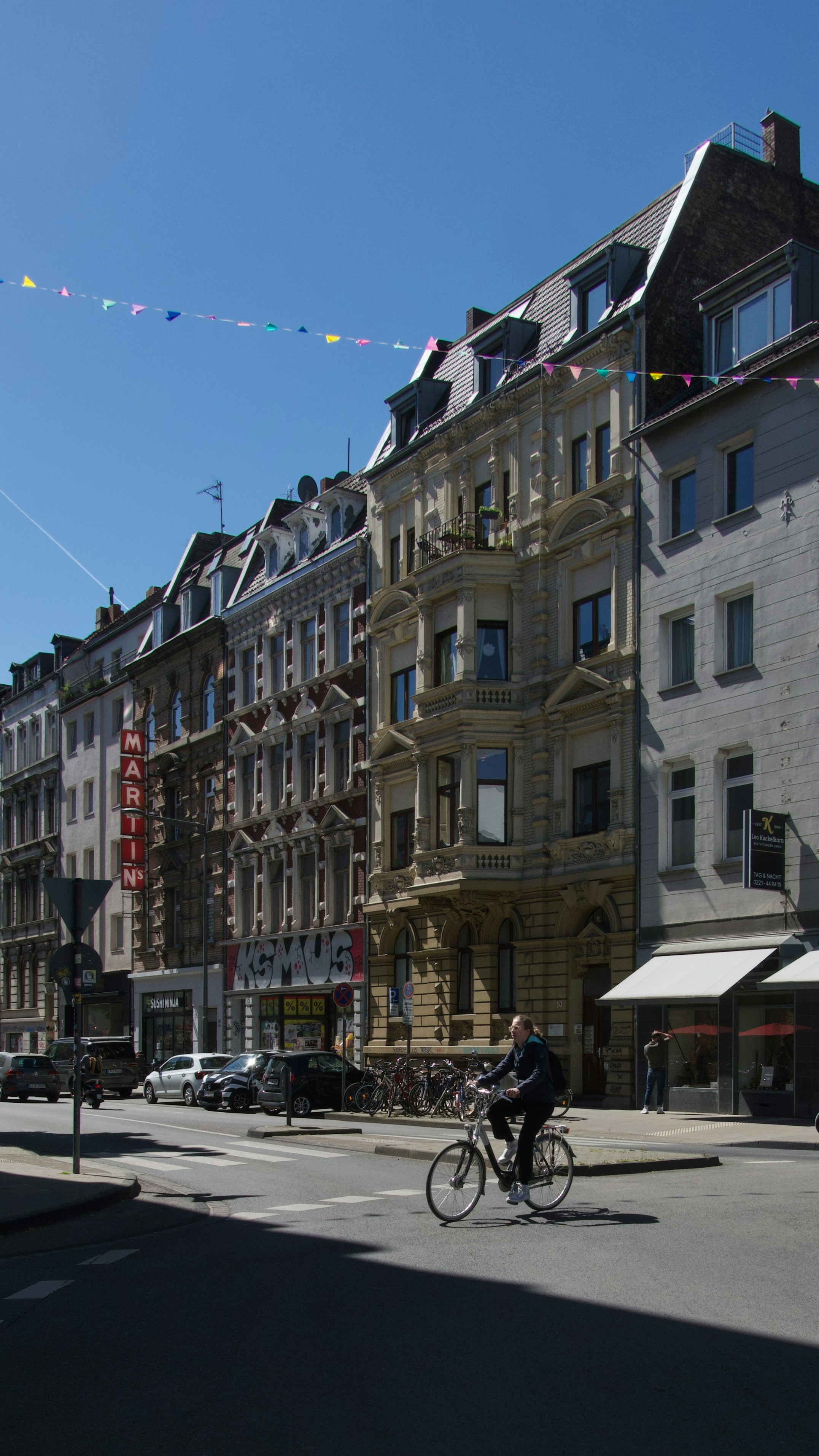 Cobbled City in Motion: Cyclist under Festive Strings