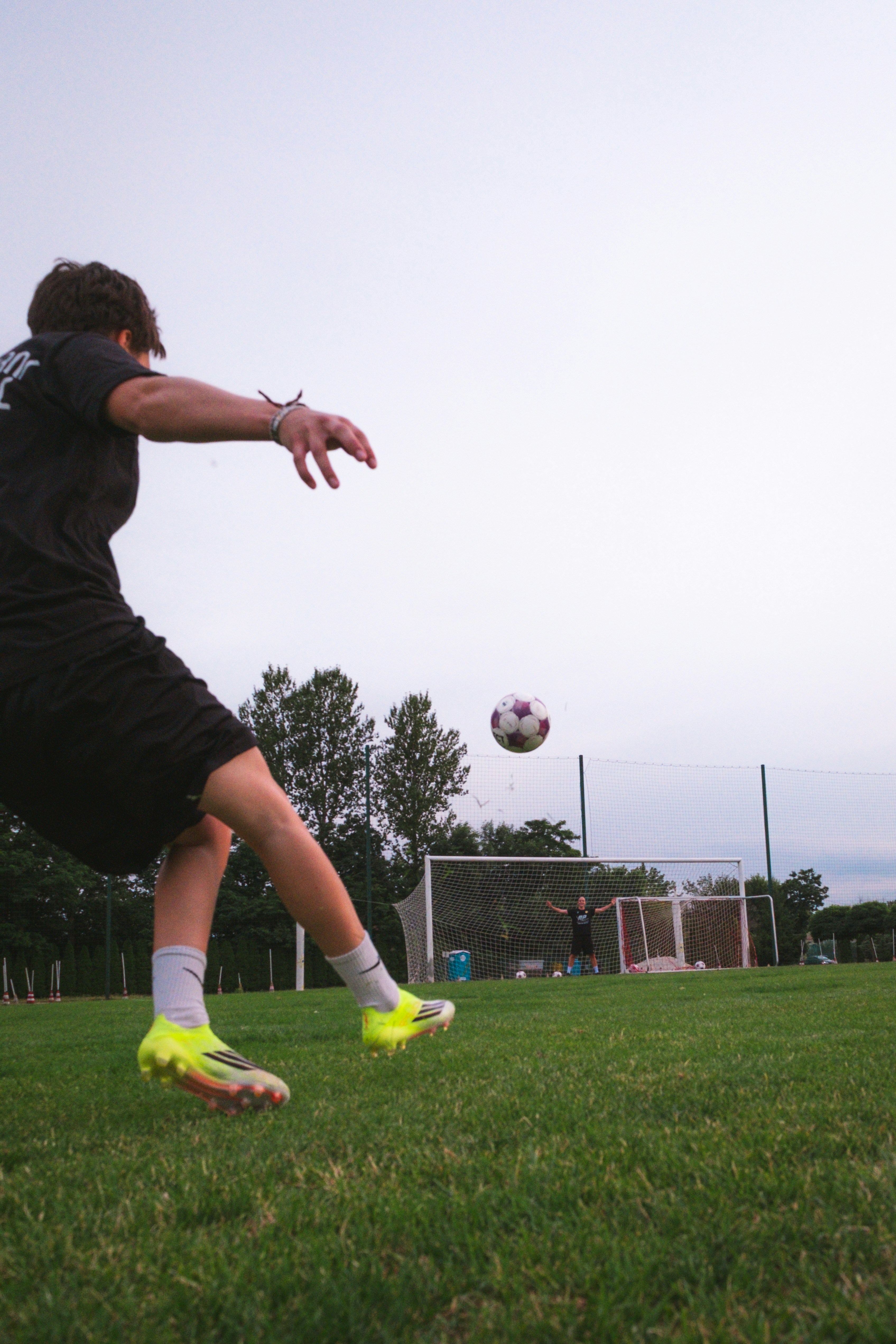 Single-footed strike toward the goal on a sunlit soccer field