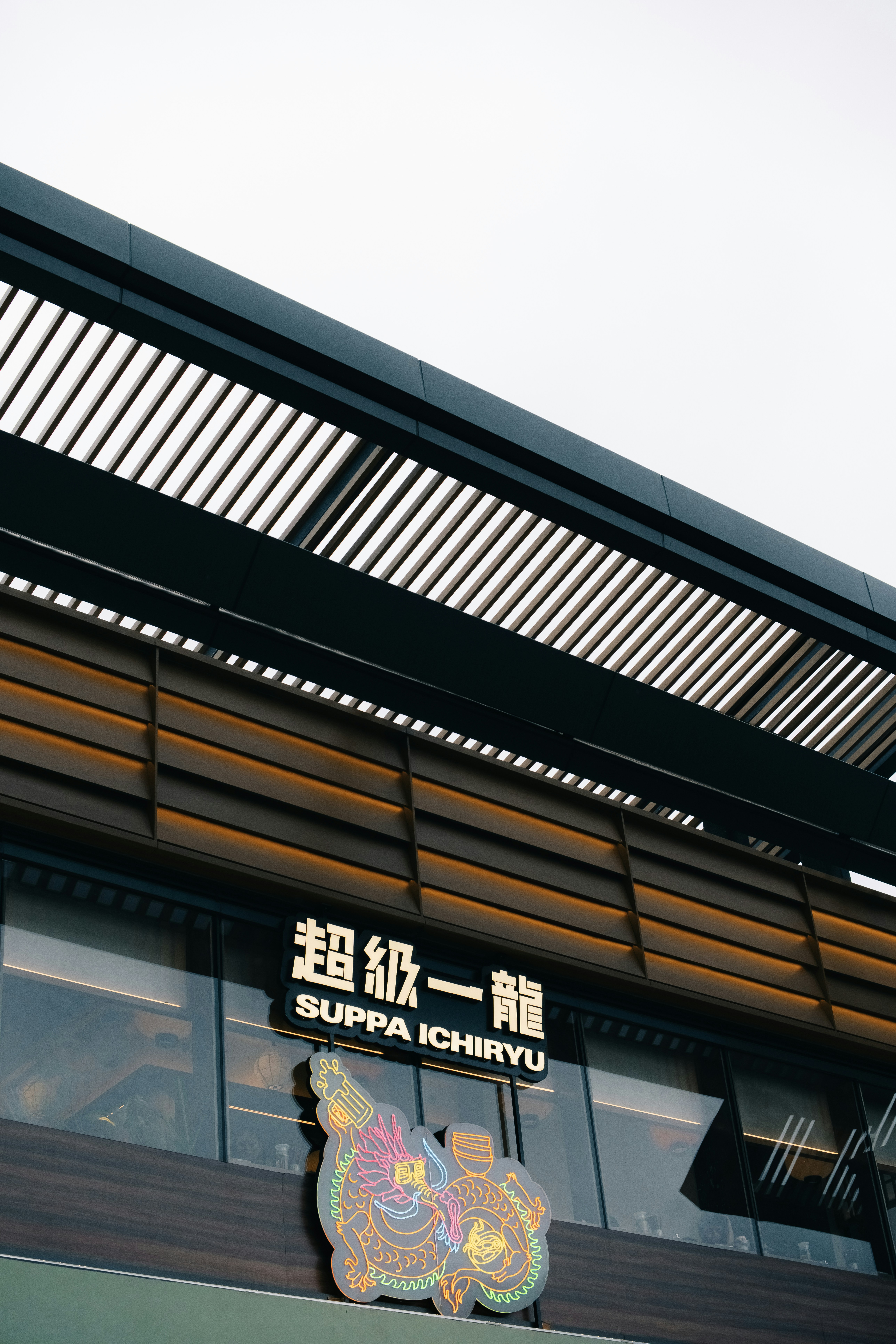 Urban Facade: Neon Sign and Striped Overhang against Sky
