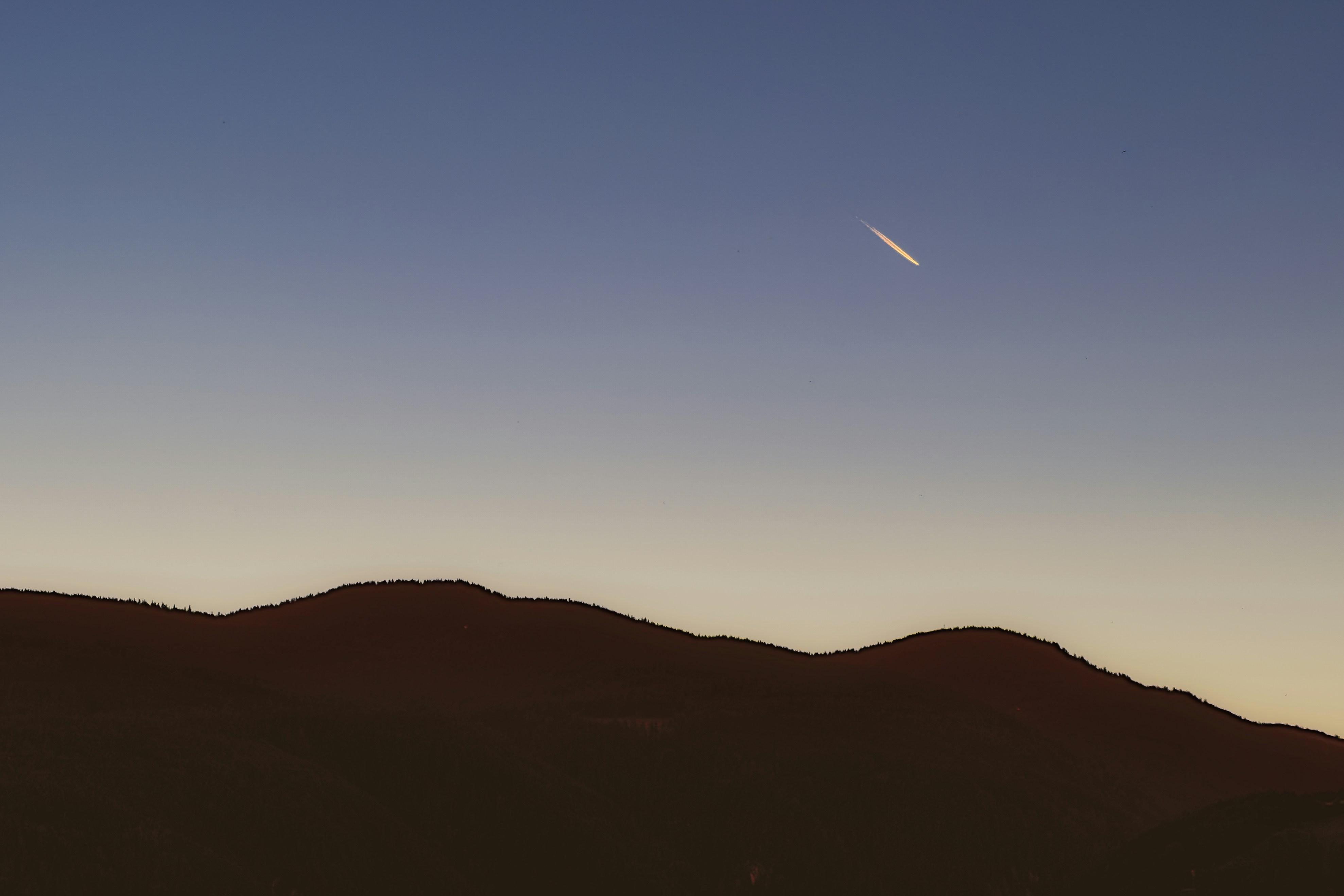 Silhouetted Hills at Dusk with a Meteor Trail