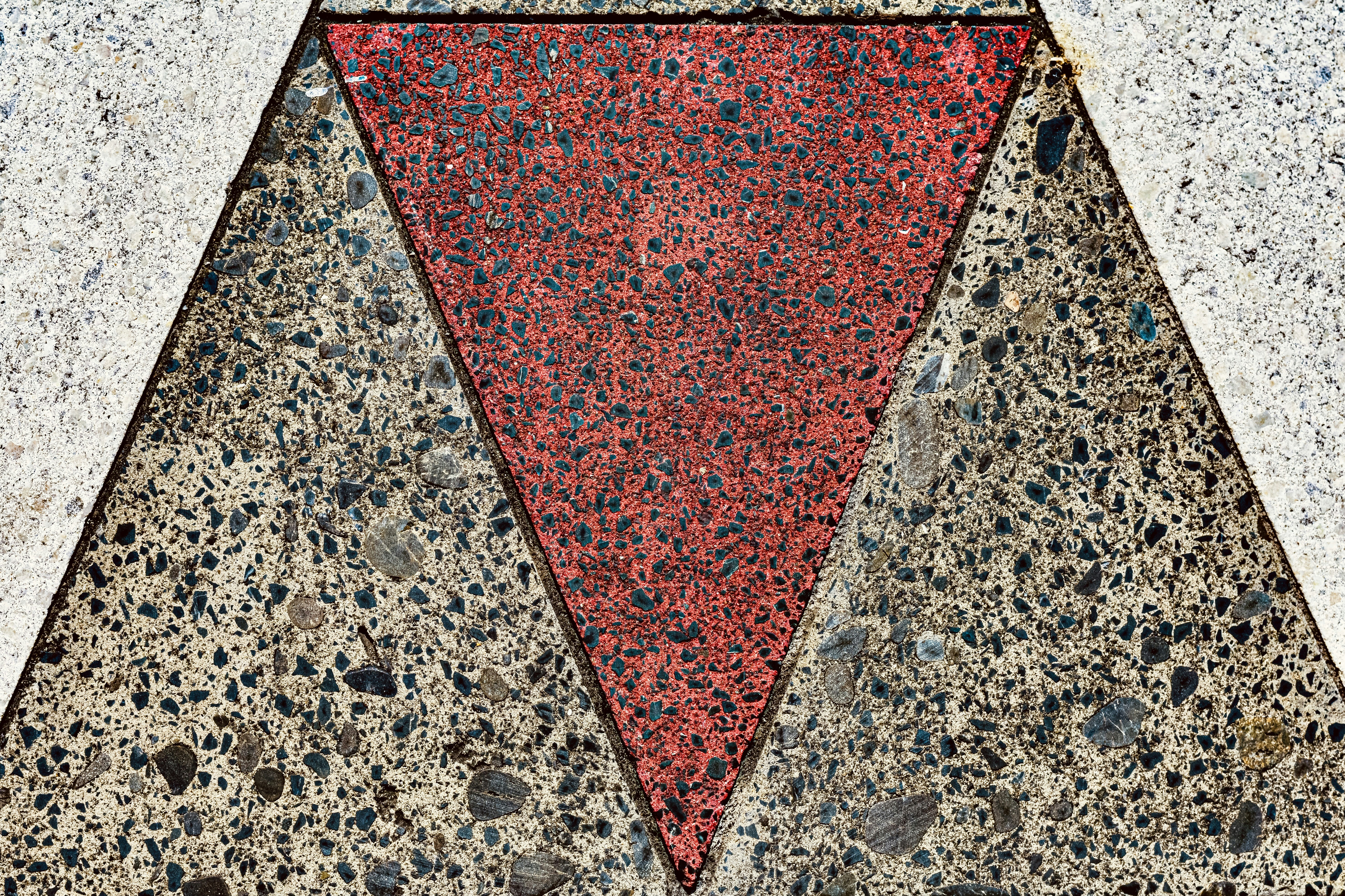 Red Triangle on Weathered Concrete: A Geometric Signal on the Sidewalk