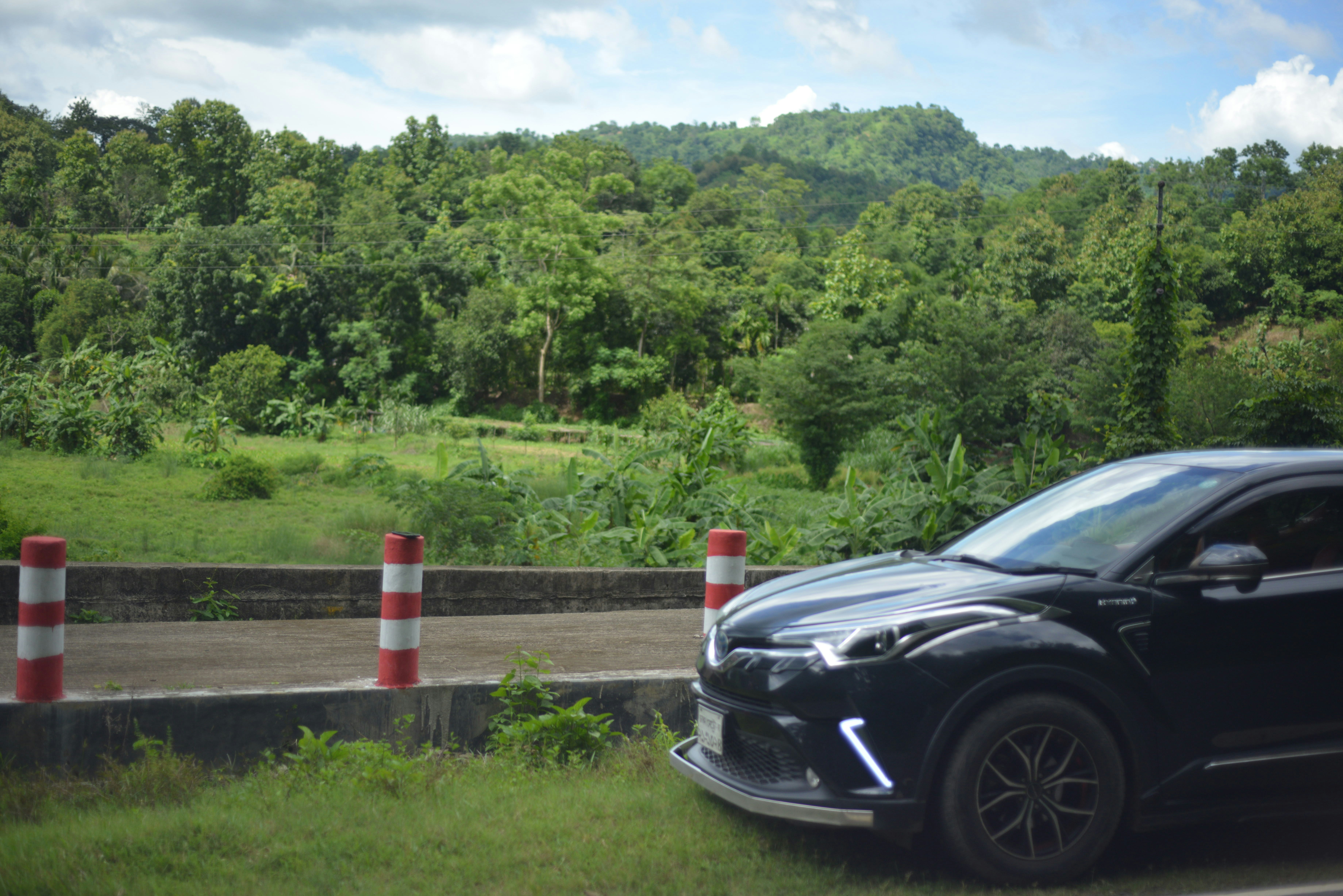 Chrome on the Curve: A Black SUV Rides by a Green Valley