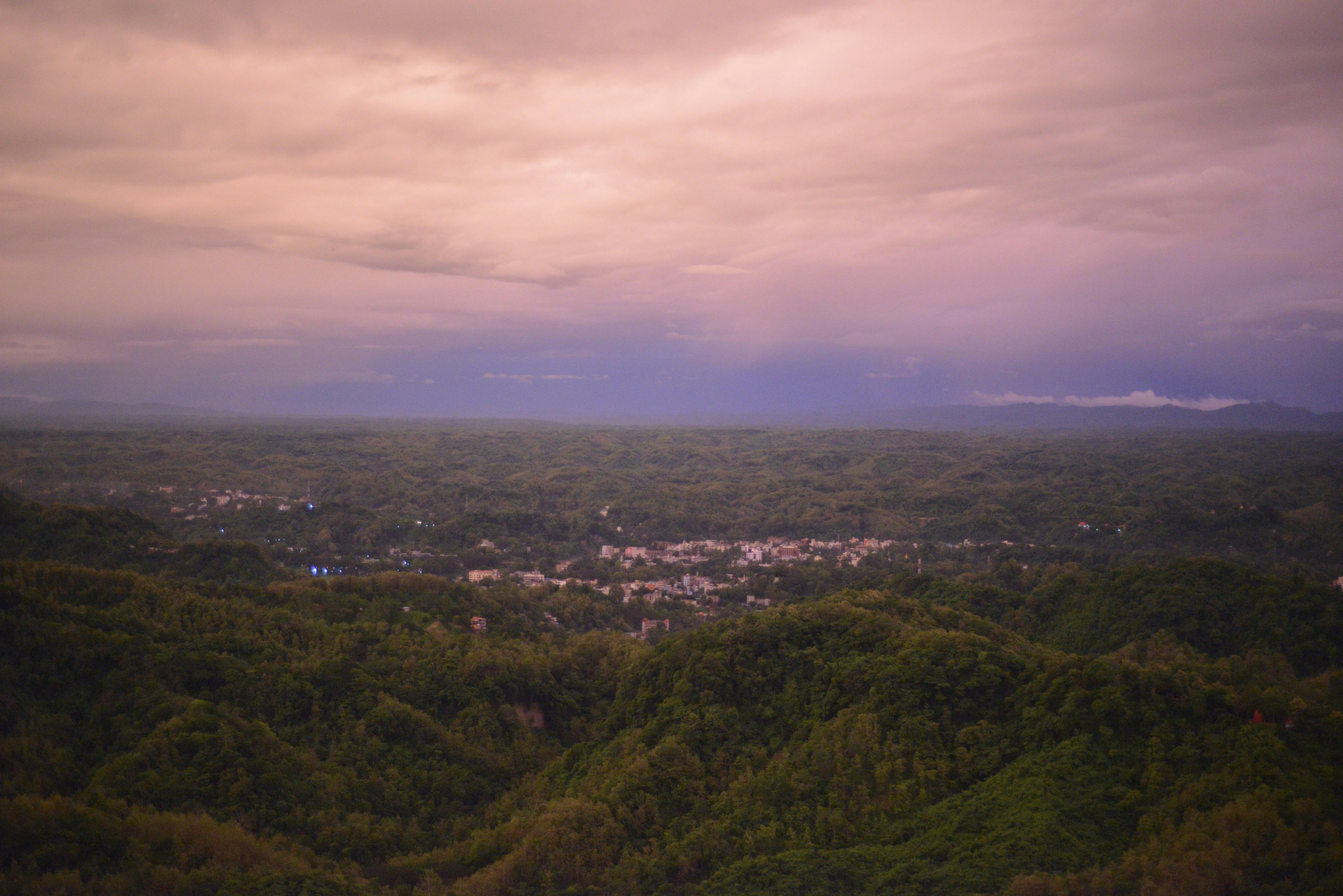 Distant Town Nestled in a Rolling Green Horizon at Dusk