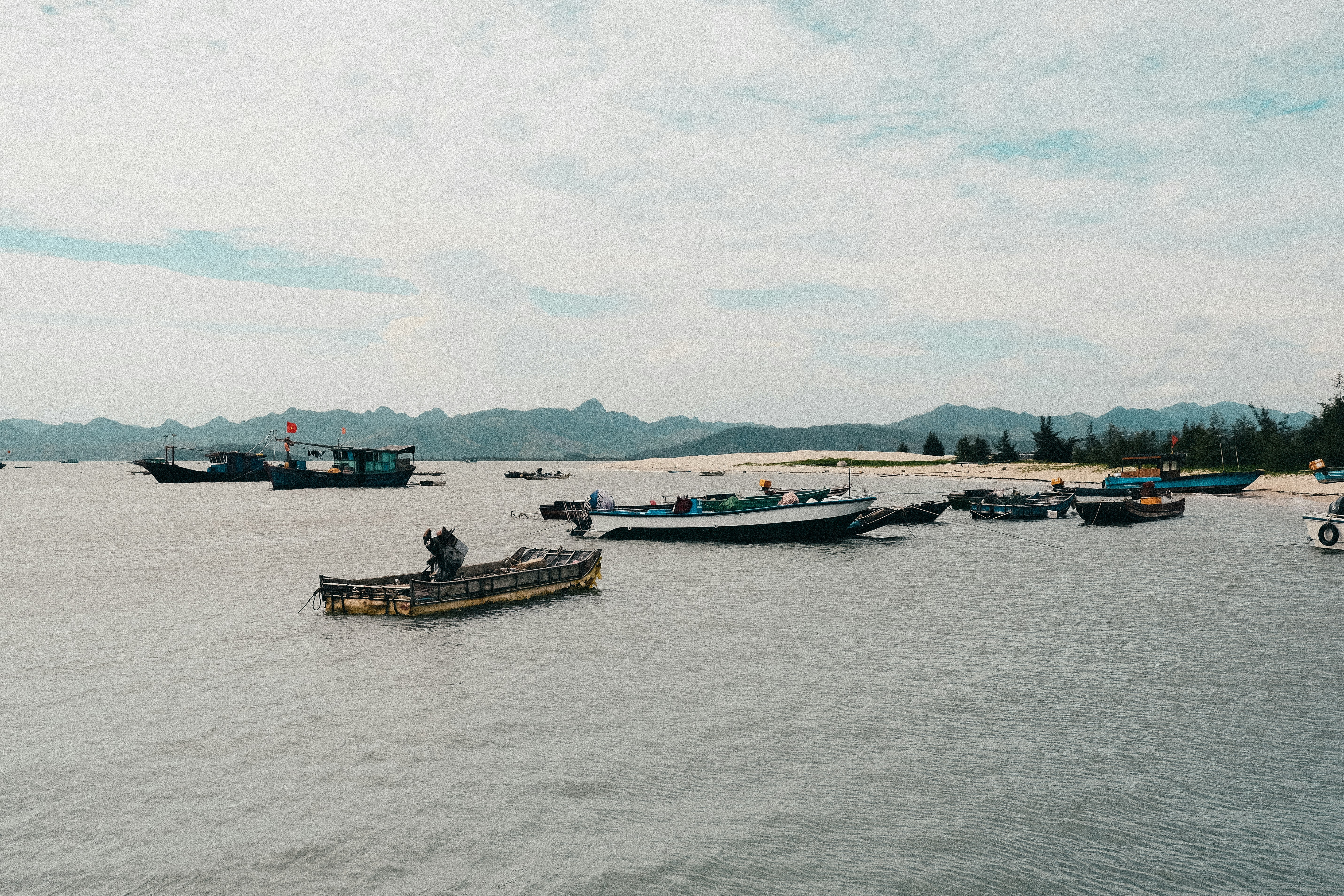 Calm harbor: boats resting in a flat, misty bay