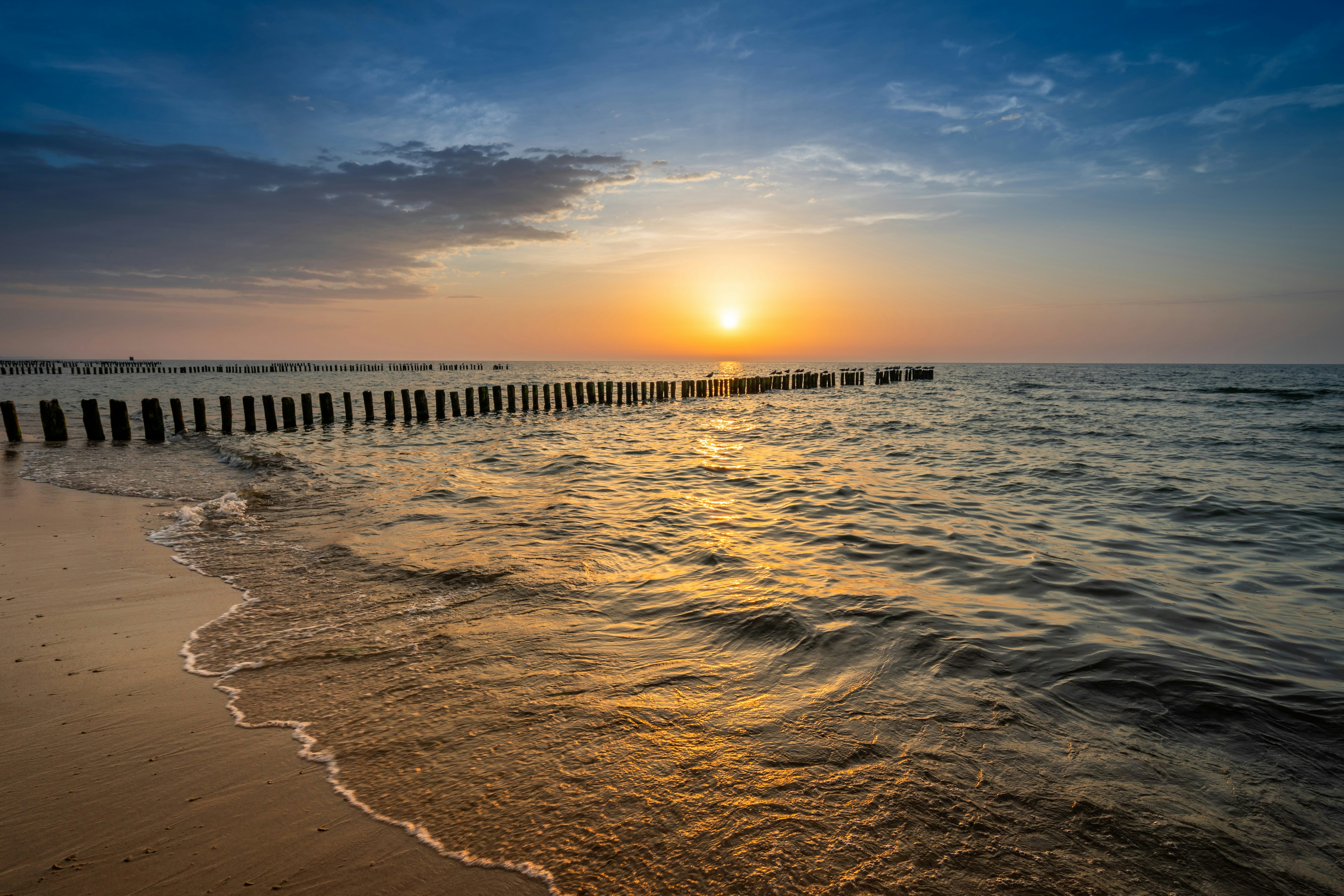Sunlit Wake: A Serene Sea Pier Stretches Toward the Horizon