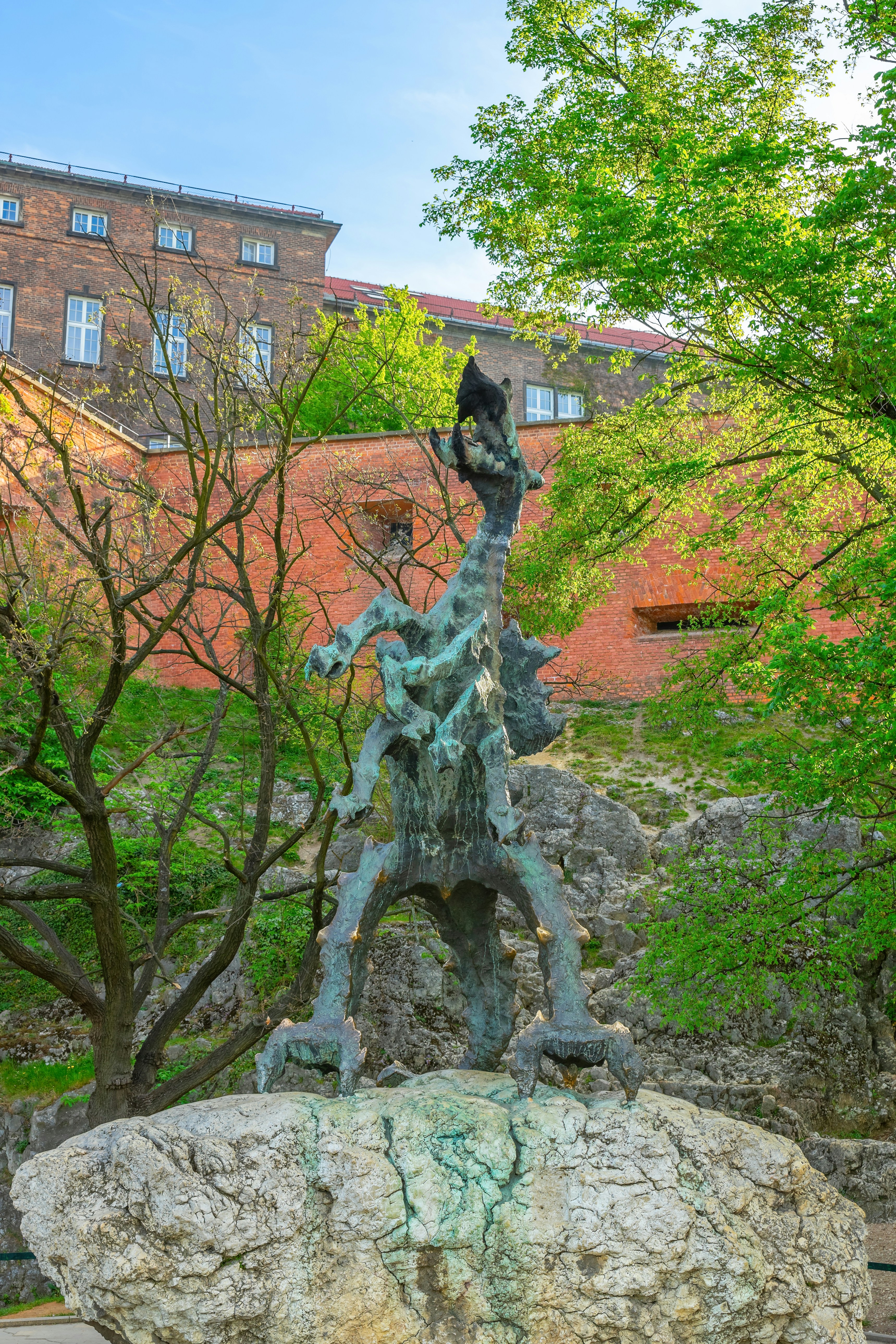 Bronze Creature Rises from Stone: A Sculptural Figure in a Green urban Garden