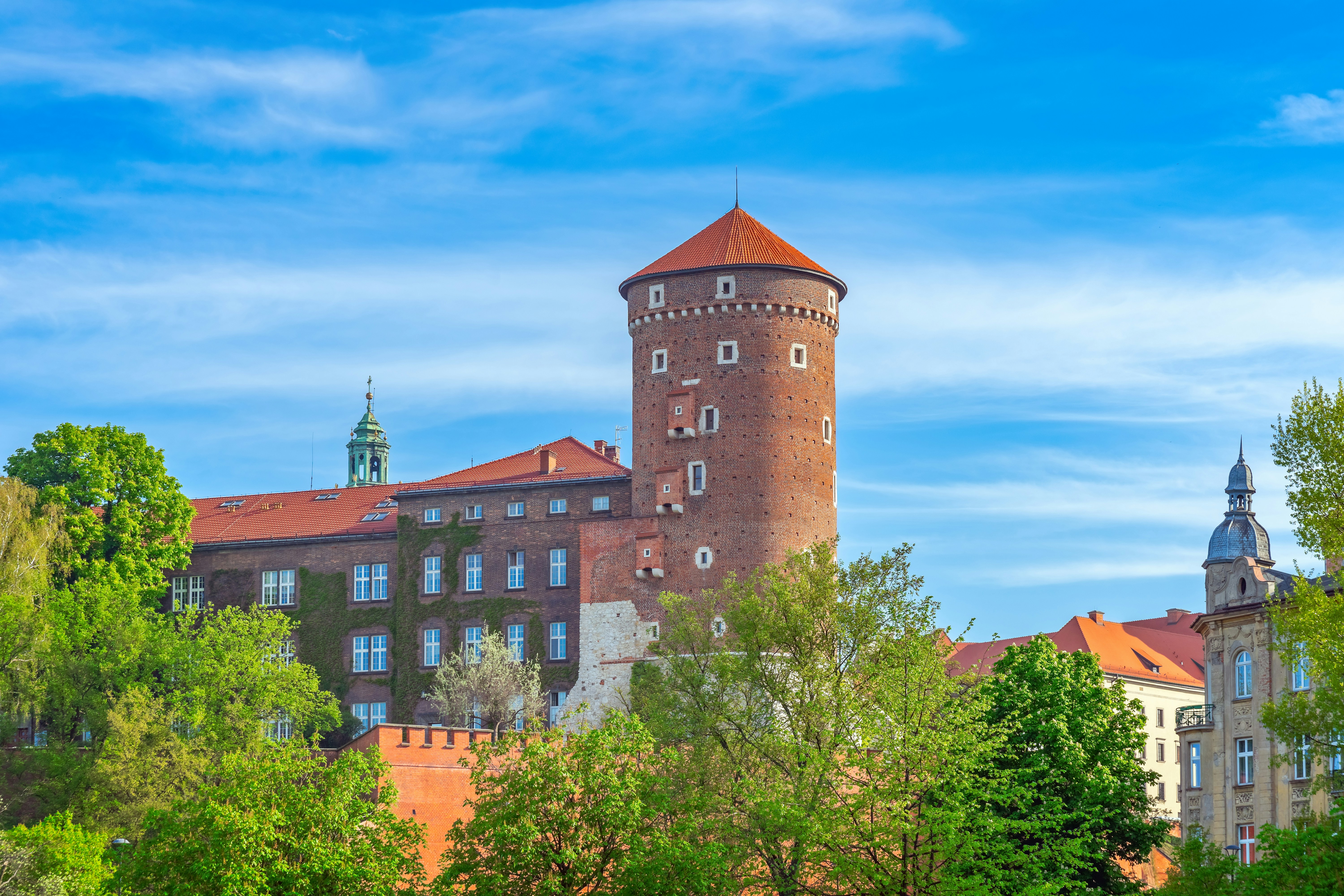 Brick Fortress Crowned by a Tower: A Riverside Castle Amid Spring Foliage