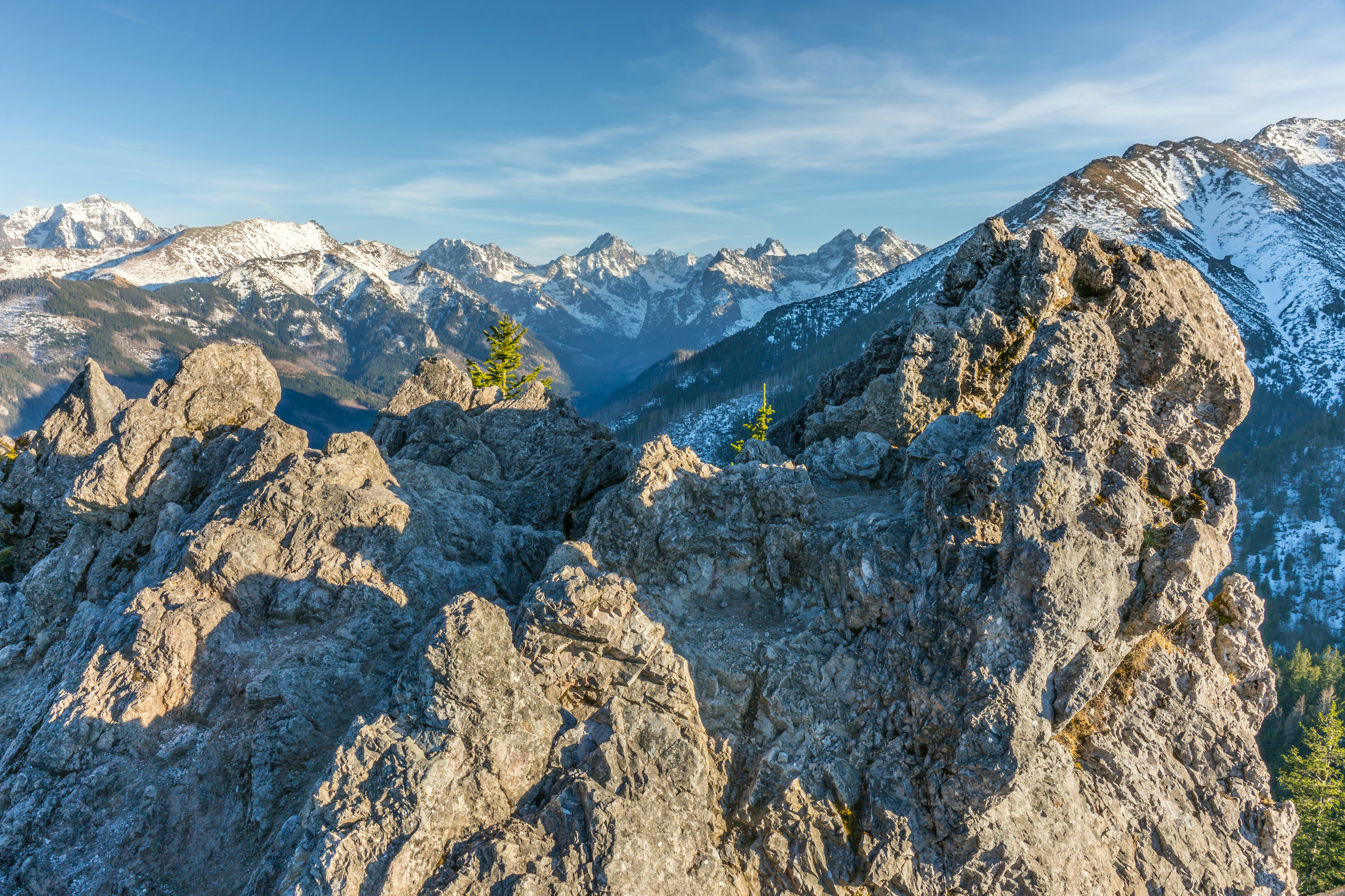 Rugged Alpine Prominence: Sunlit Crags Against a Snow-Capped Horizon