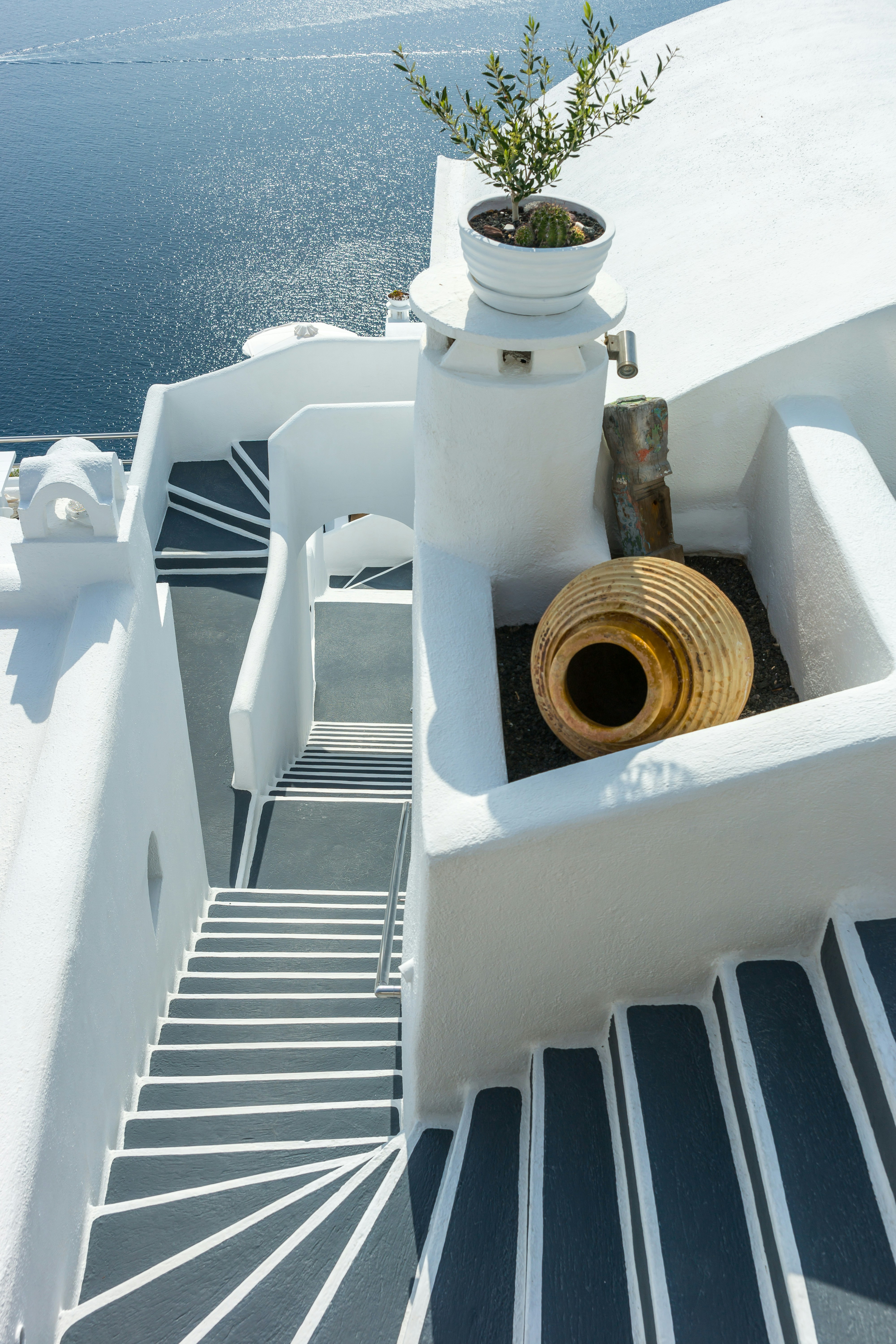 Whitewashed stairs descend to a sunlit sea terrace in Santorini