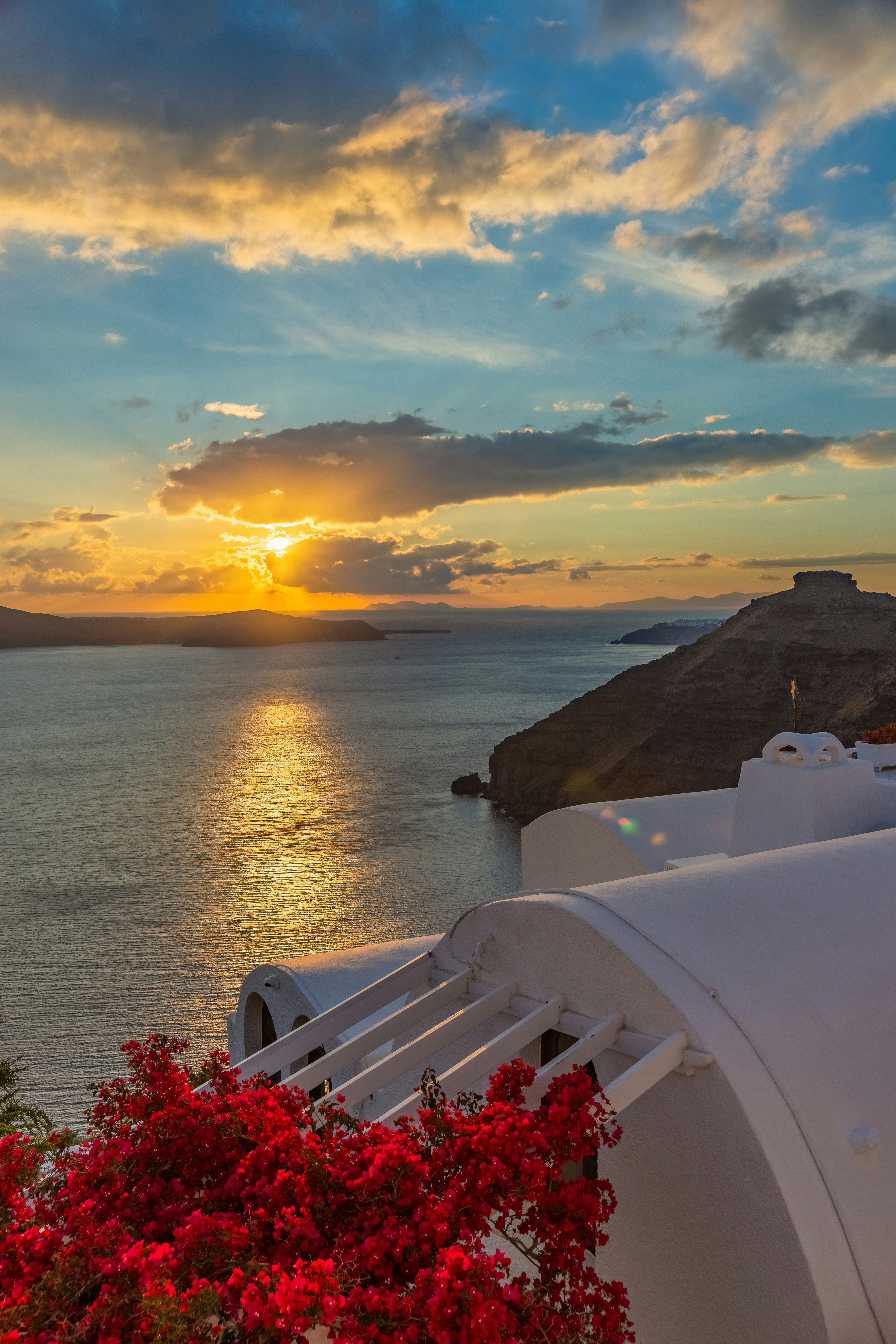 Sunset Over the Caldera: Whitewashed Architecture Framed by Red Bougainvillea