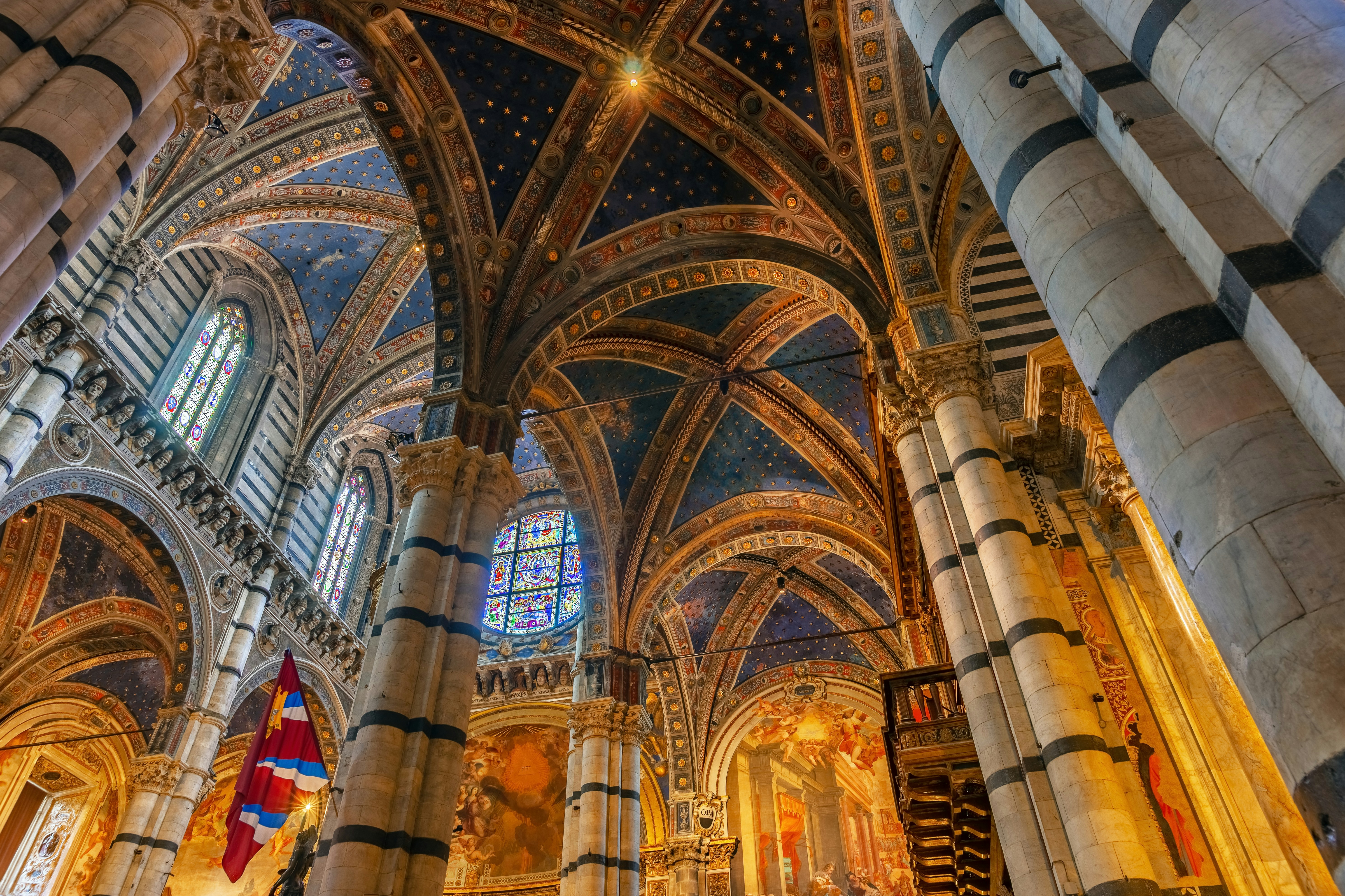Gilded Vaults: Sunlit Cathedral Interior with Stained Glass and Marble Columns