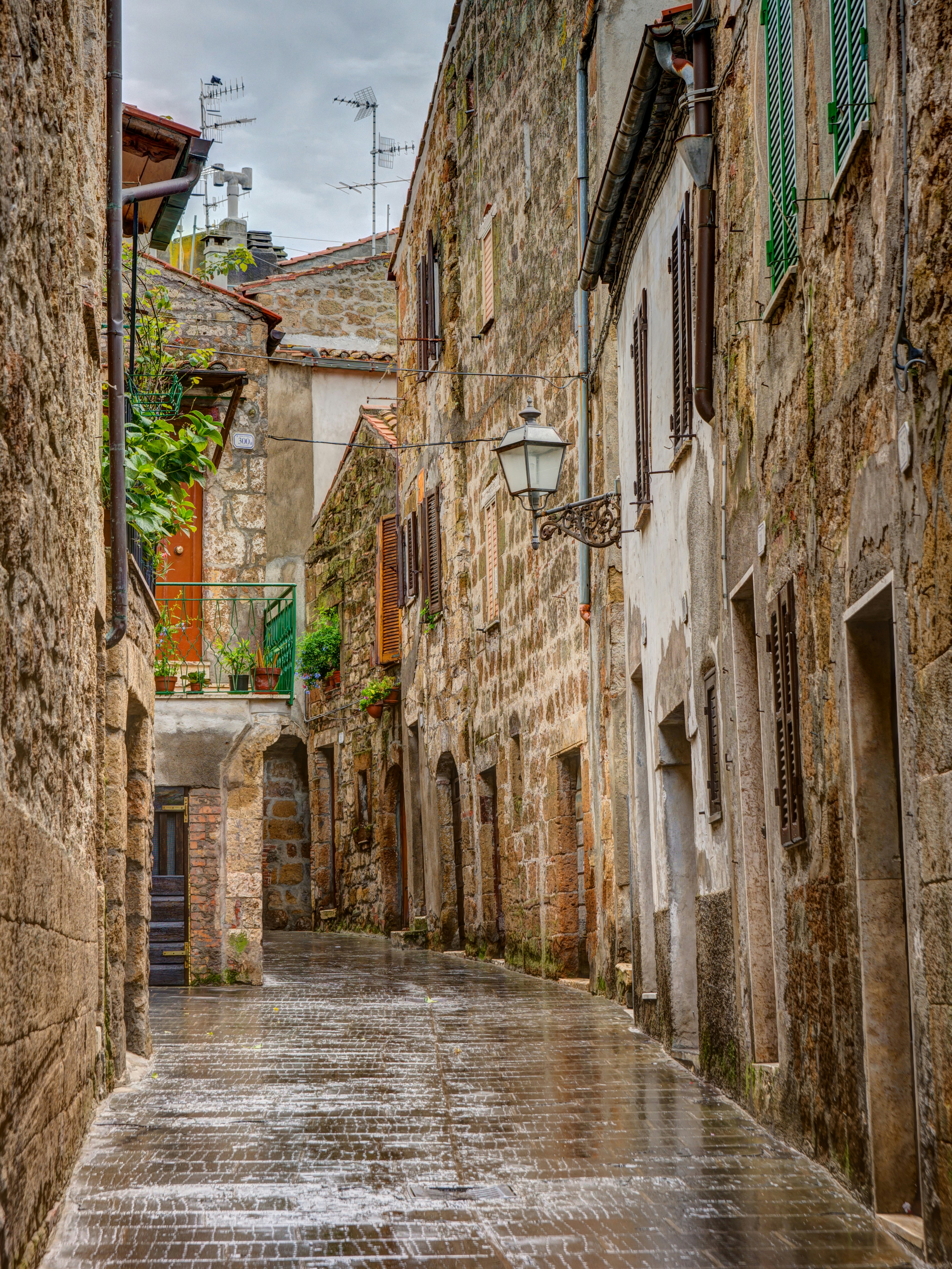Stone Alley in the Rain: Narrow Italian Passageway with Mossy Facades
