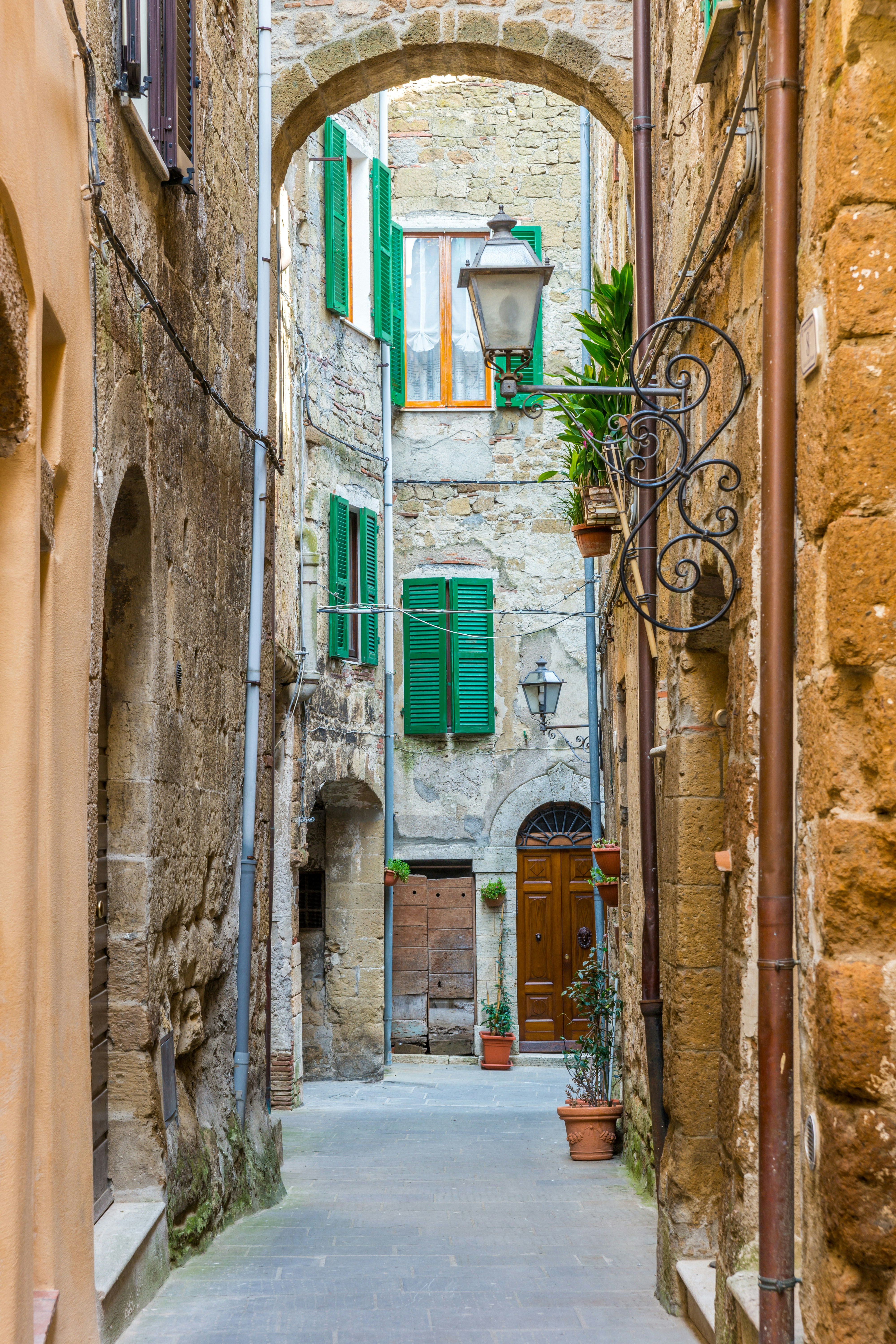 Sunlit Narrow Alley of Aged Stone and Green Shutters