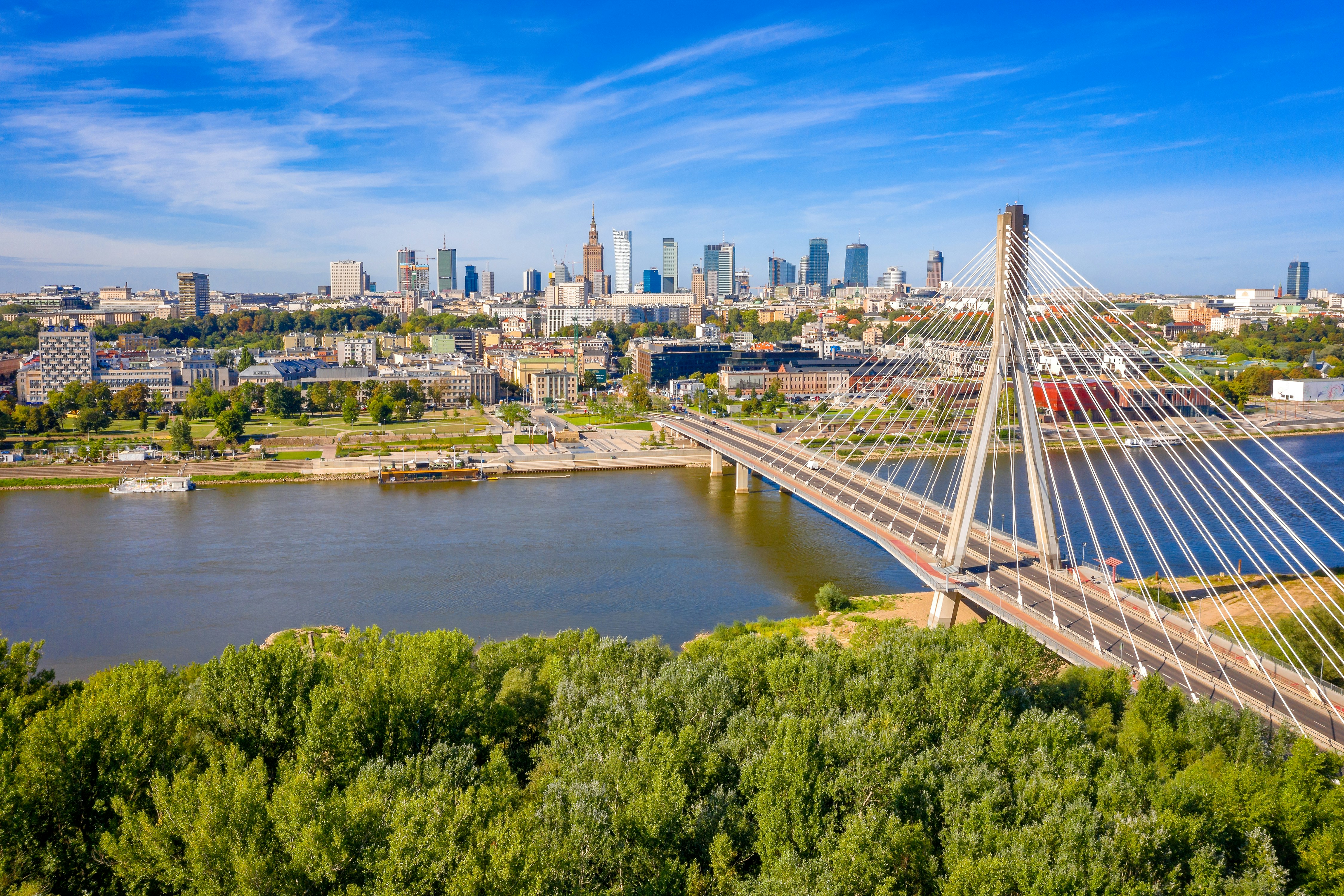 Cable-stayed bridge spanning a winding river with a cityscape backdrop