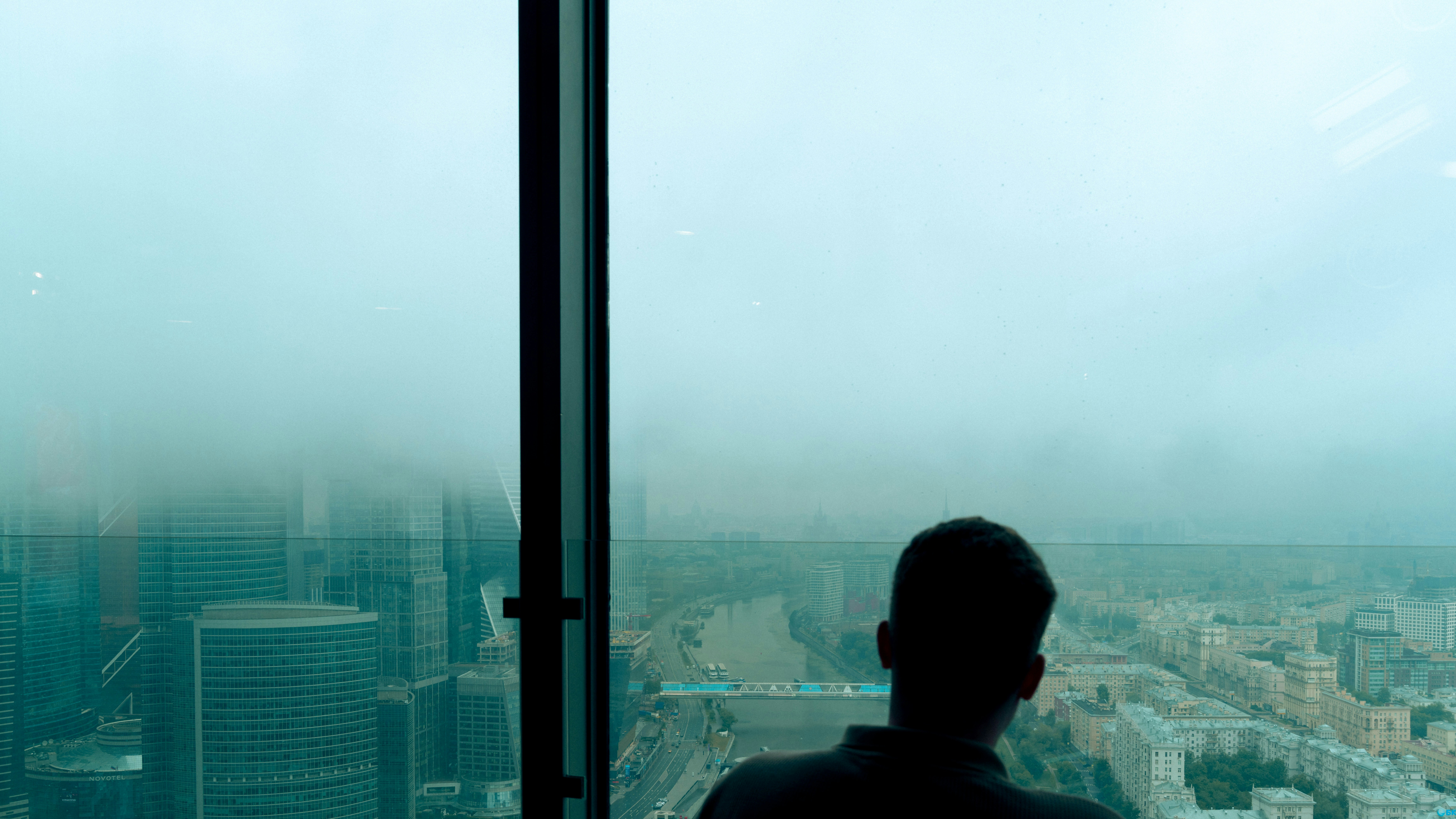 Silhouetted Observer in a Misty Skyline Atrium