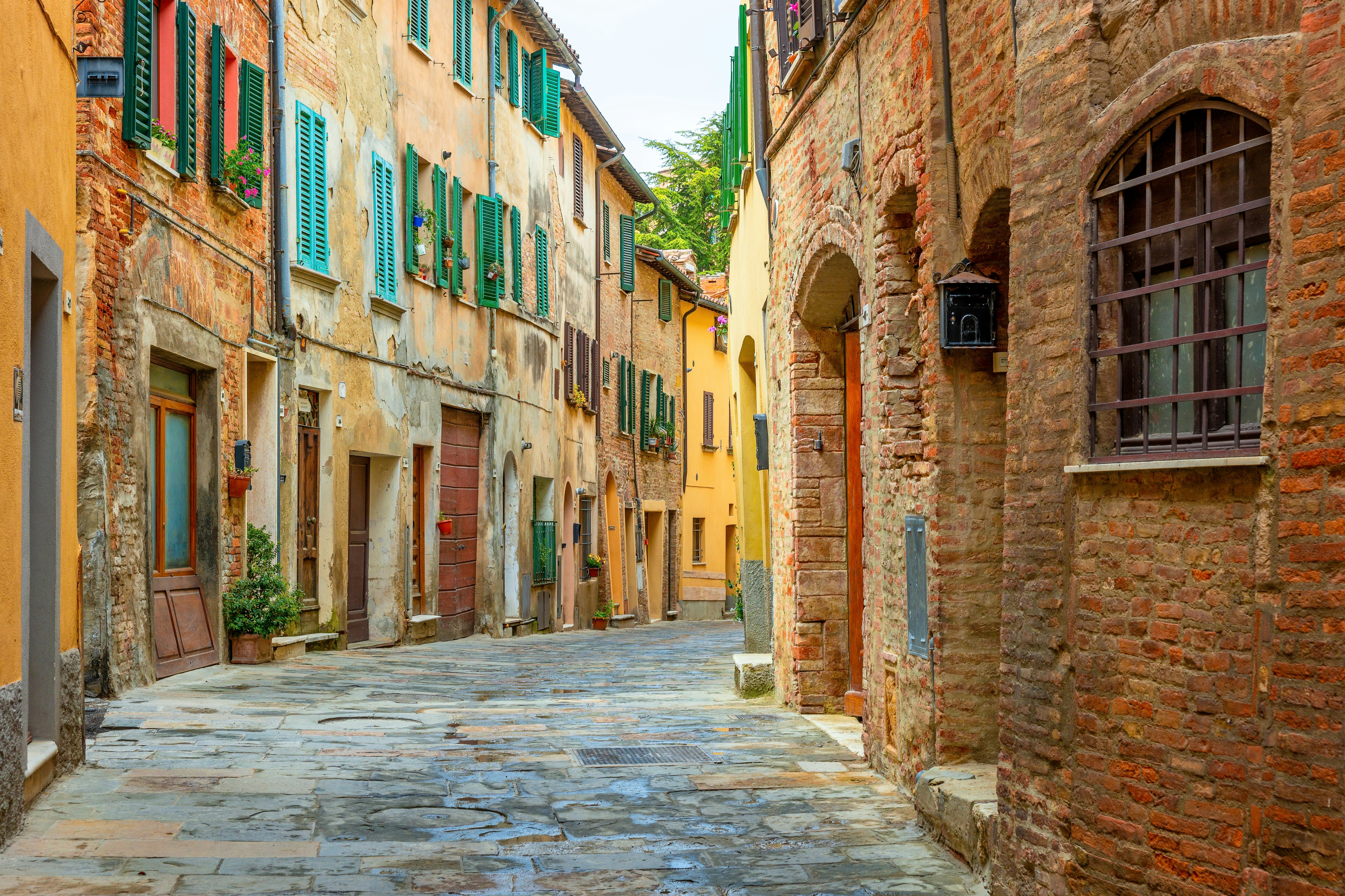 Sunlit Tuscan Lane: Colorful Facades and Timeworn Brickwork