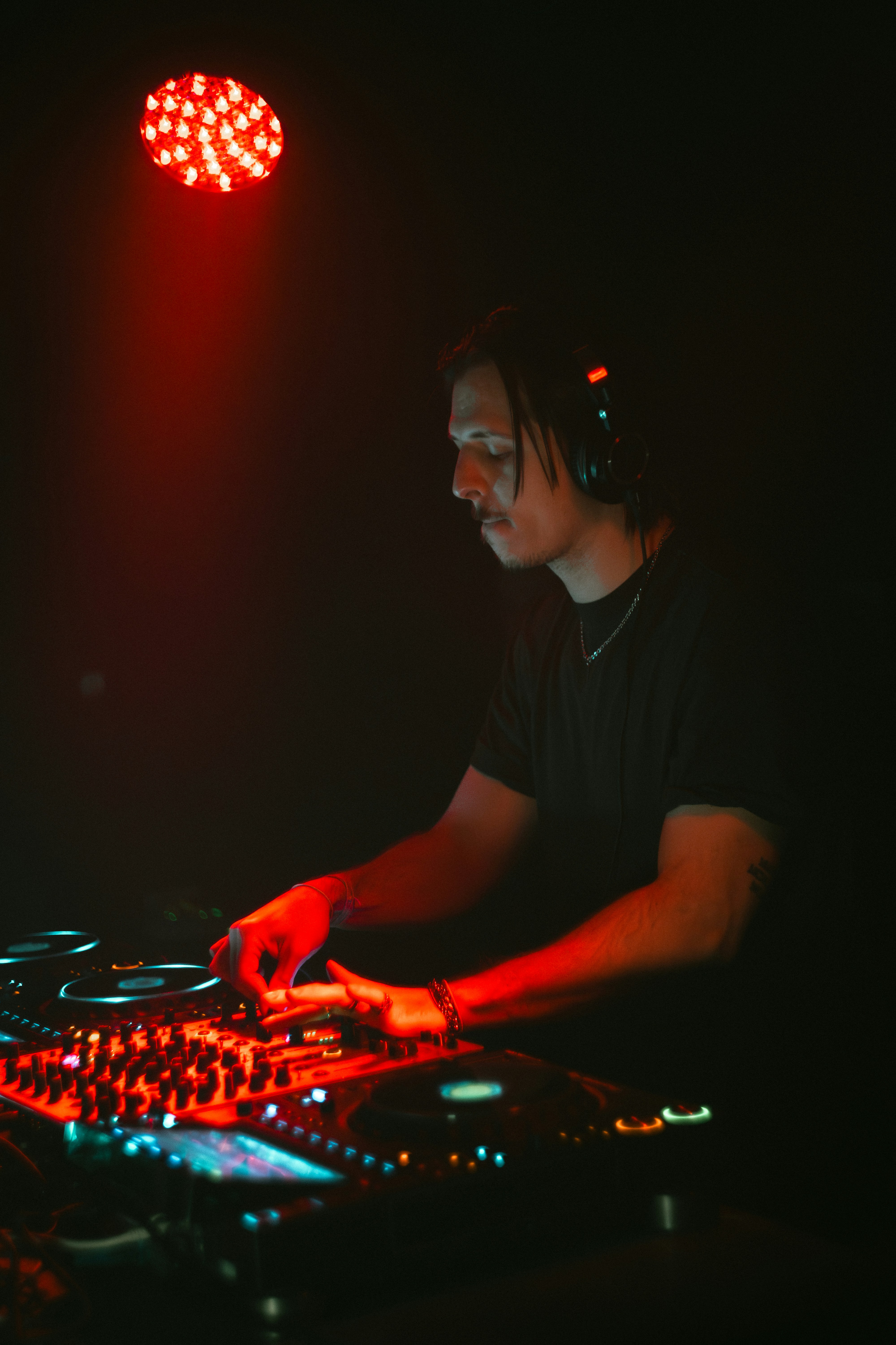 Red Pulse: DJ at the Mixer Under a Single Crimson Spotlight