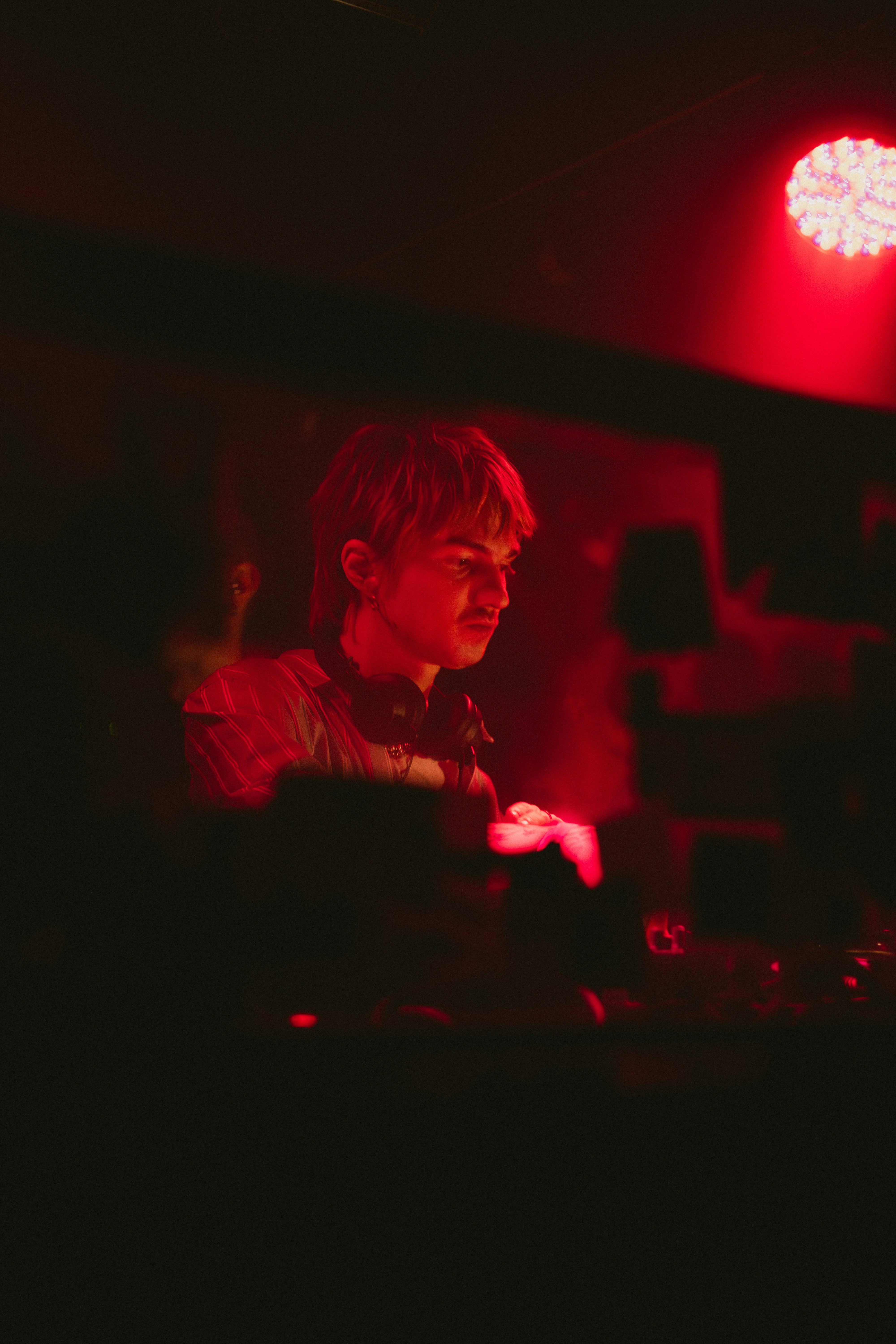 Red-lit Focus: The DJ in the Dusk Club