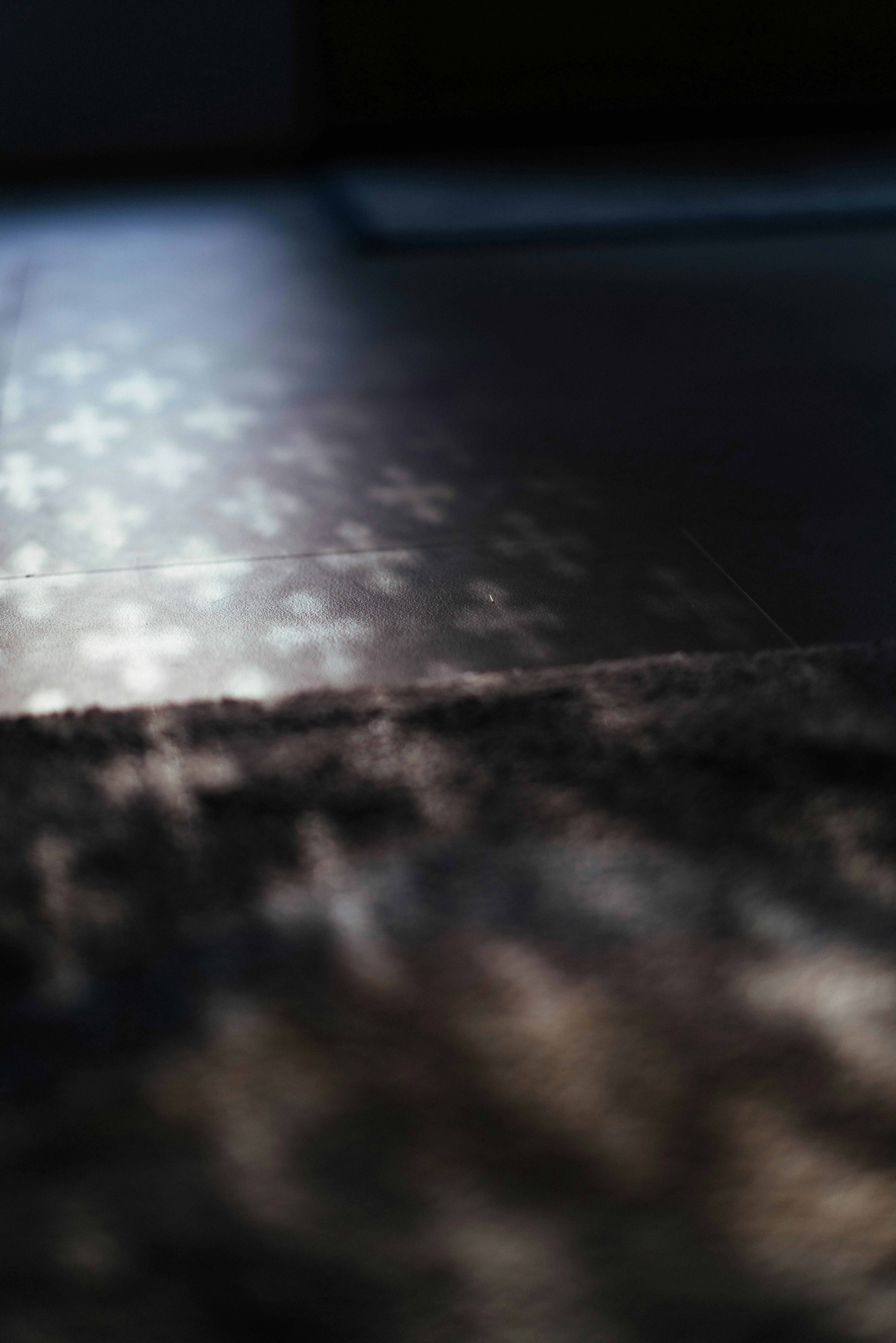 Softly lit floor surface with bokeh patterns and a darkened edge, suggesting an abstract indoor scene with subtle texture.