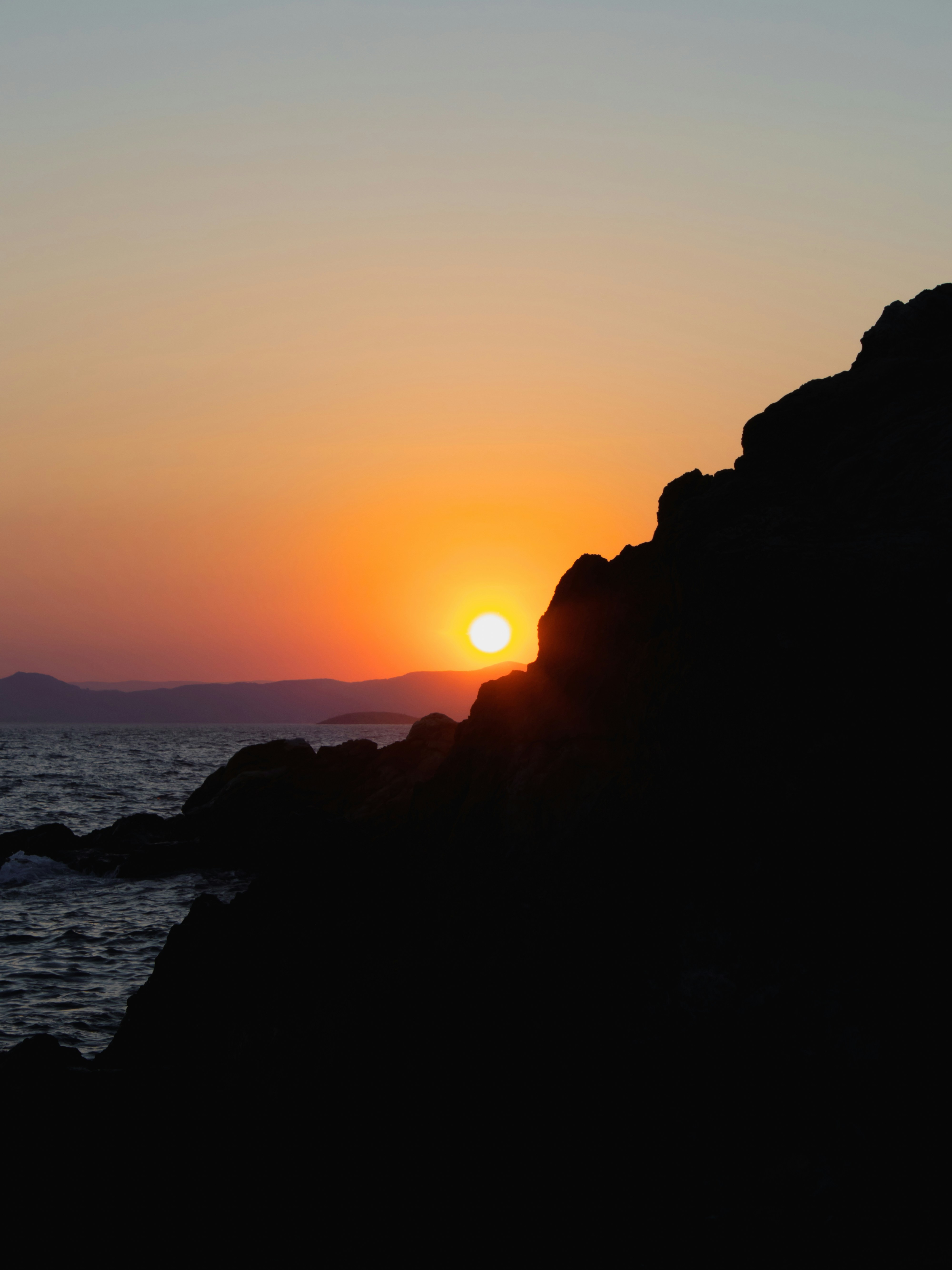 Sunset Seaward: A Quiet Climb of Light over Darkened Cliffs