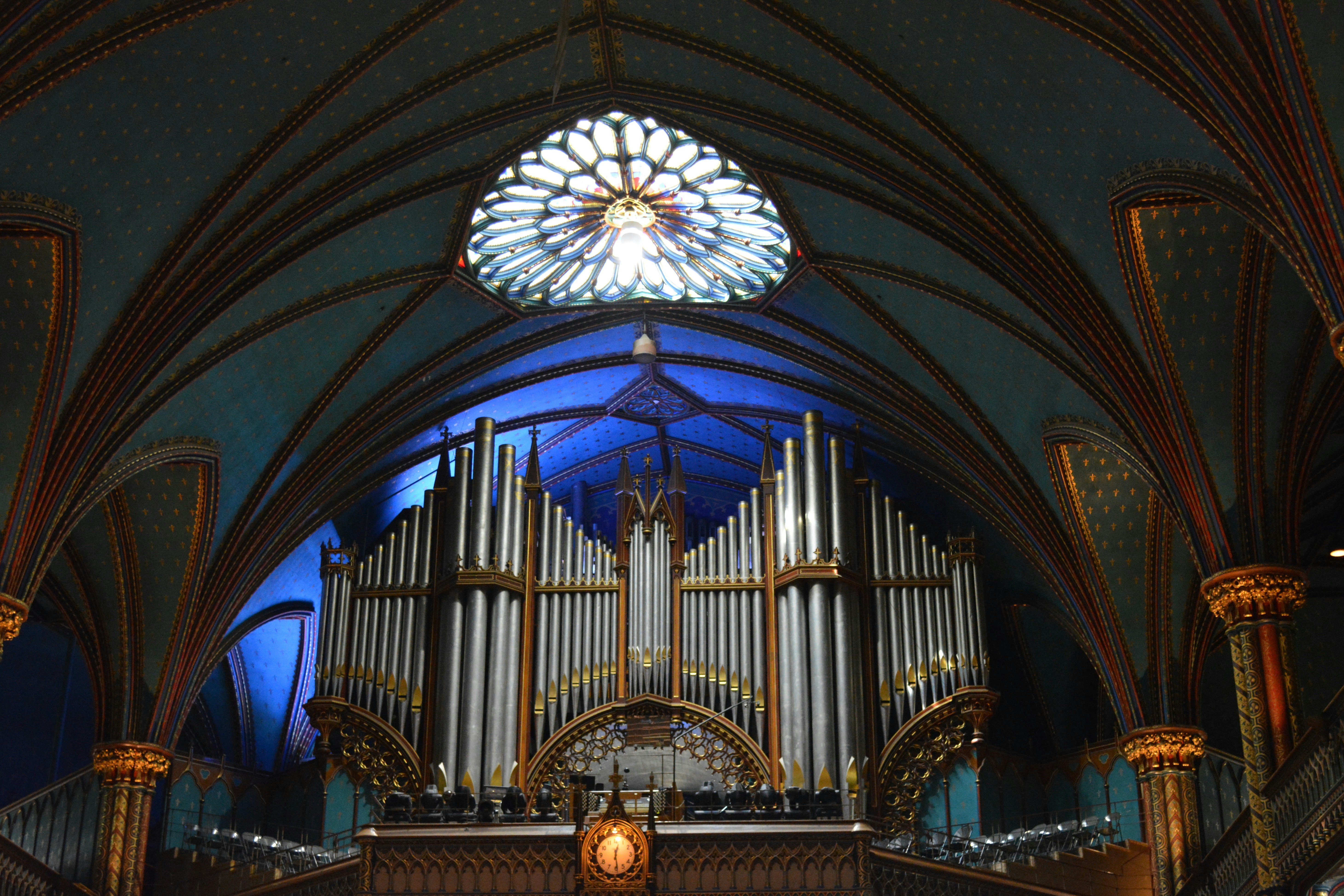 Organ pipes beneath a stained-glass arch in a gothic church