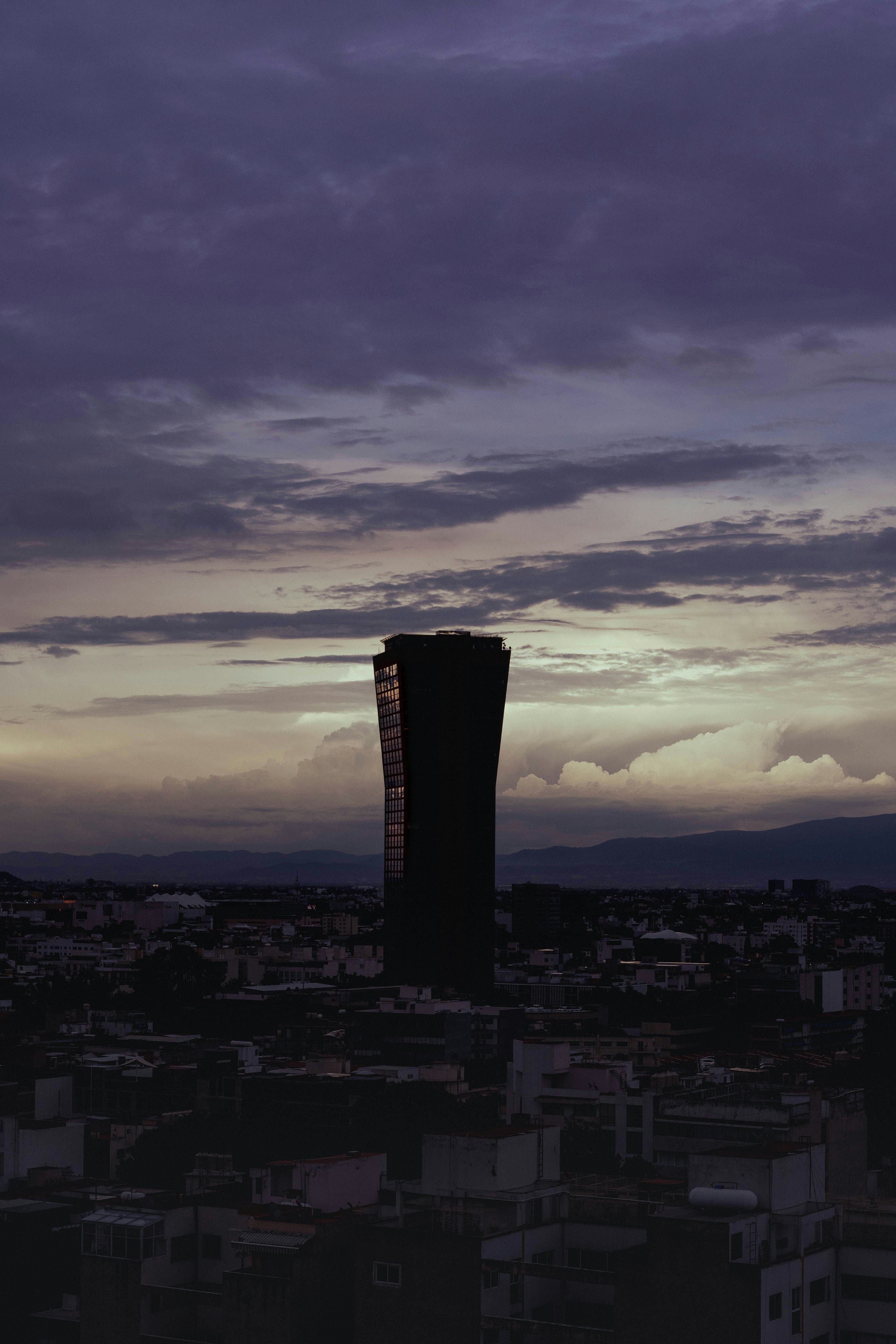 Silhouetted Skyscraper at Dusk: A City Quiet Under Clouded Sky