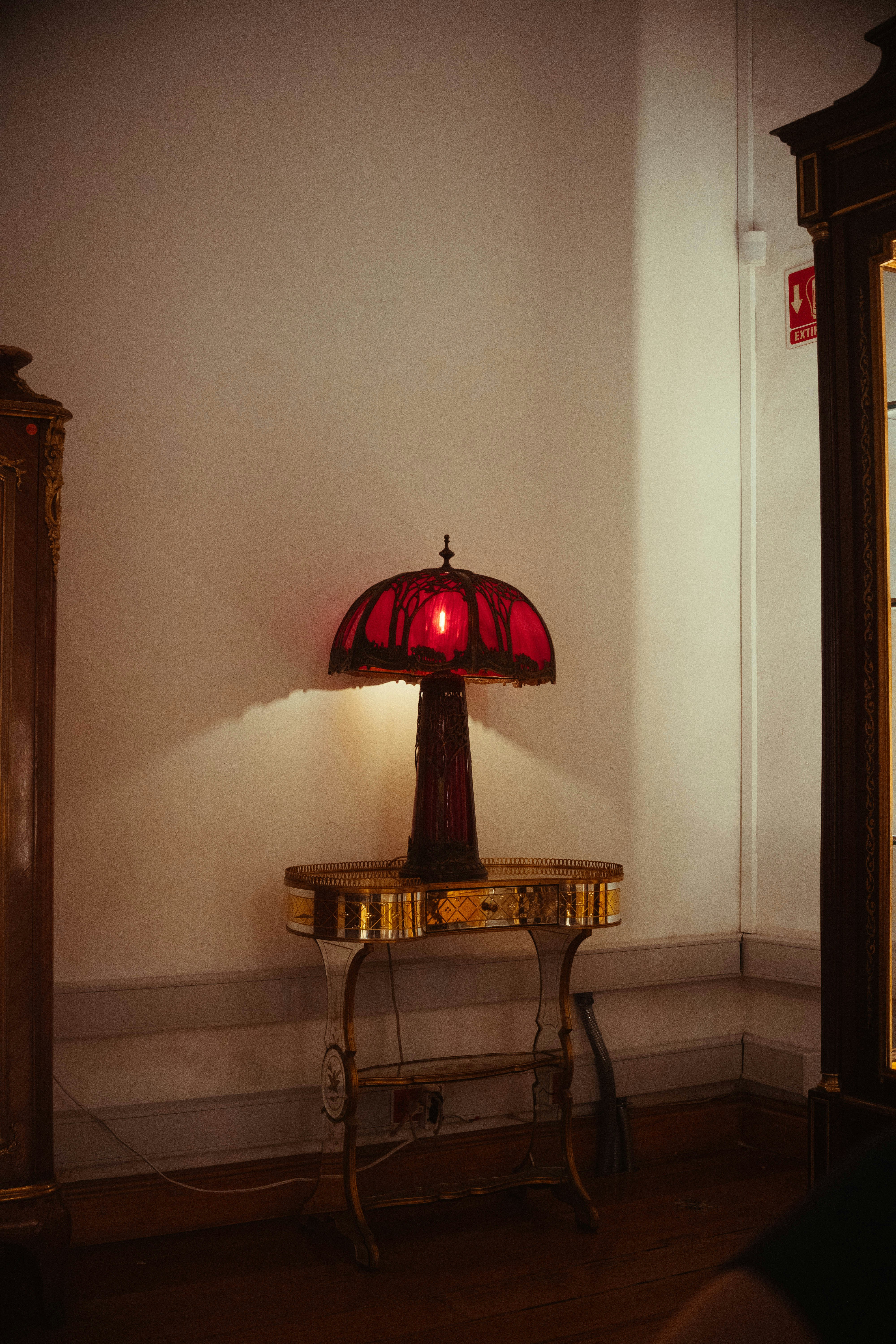 Red Glass Lamp on Ornate Table in Dim Corner of Classic Interior