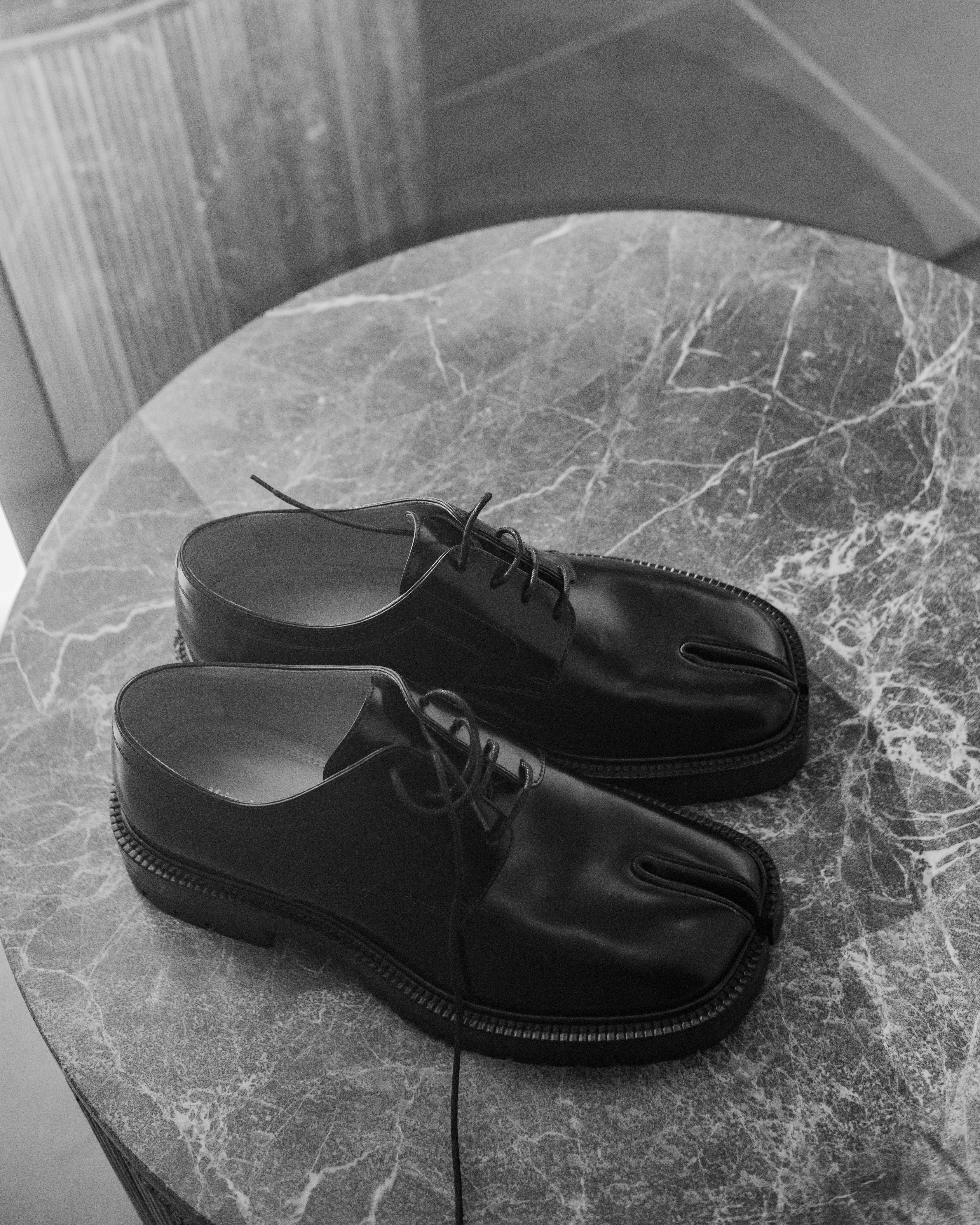 Polished Black Shoes Resting on Marble Table