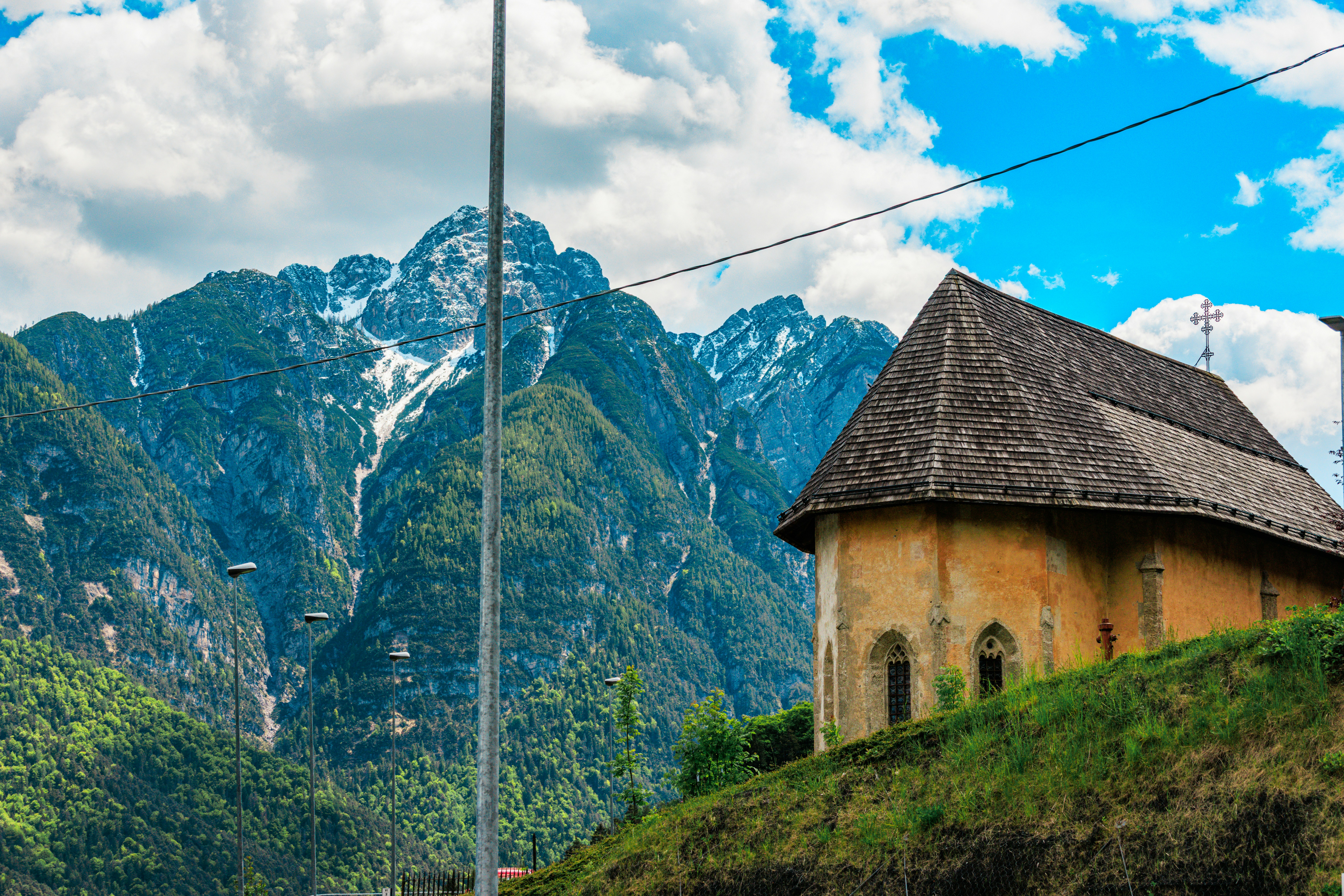 Stone Hut on a Verdant Slope Under Alpine Peaks