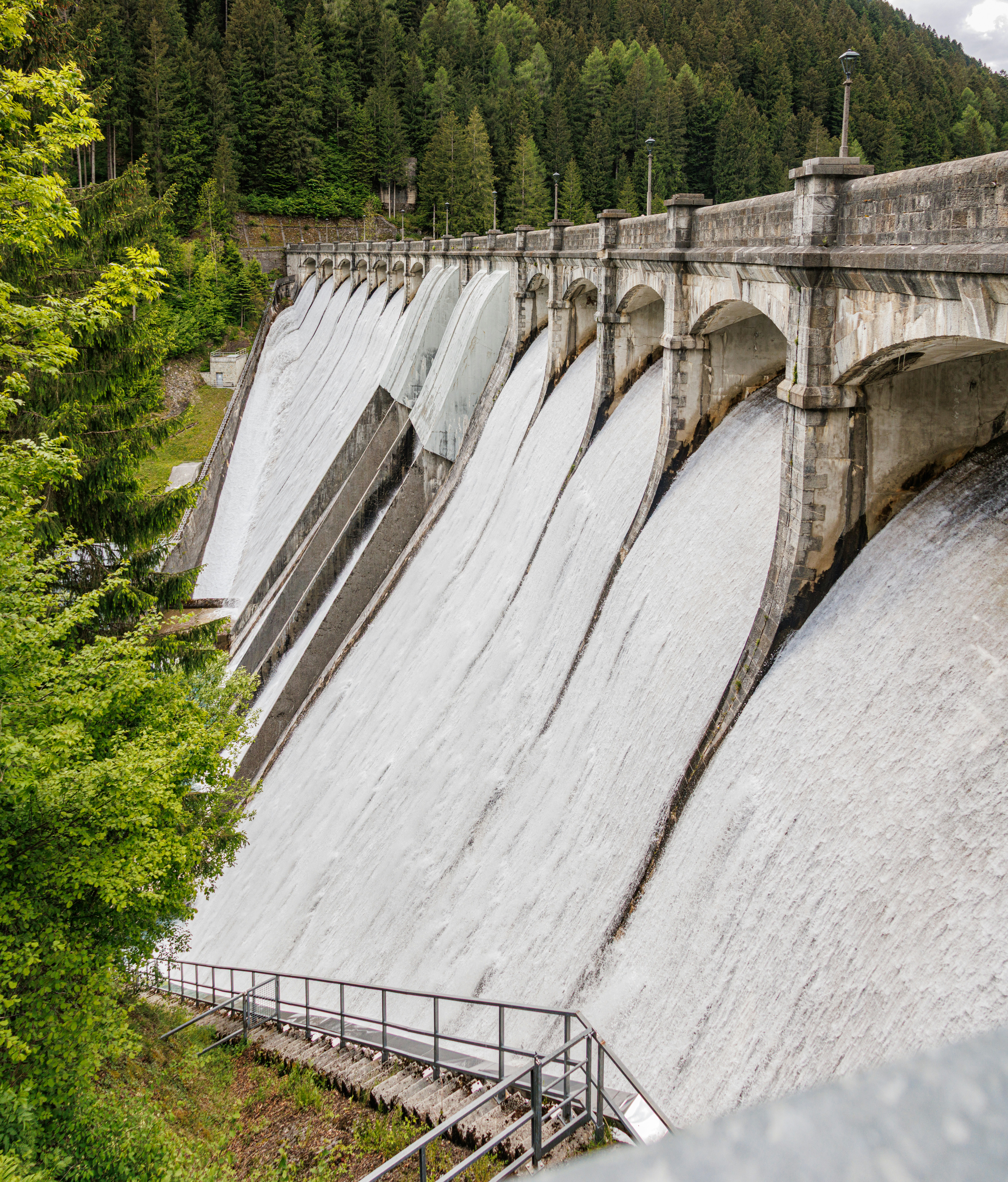Cascade of Concrete: A Dam Brimming with White Water and Green Surroundings